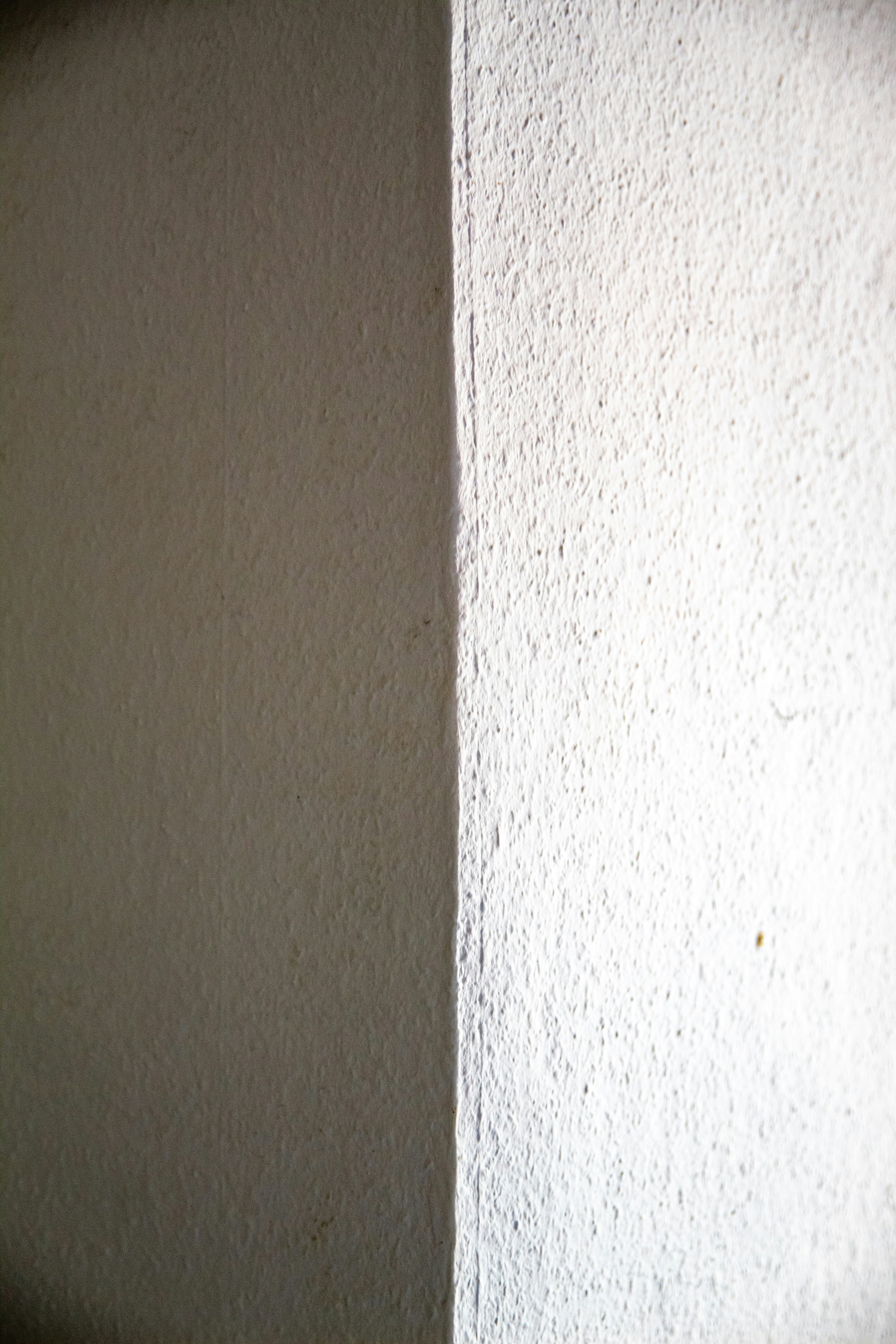 Textured wall corner with contrasting light and shadow, highlighting the surface details.
