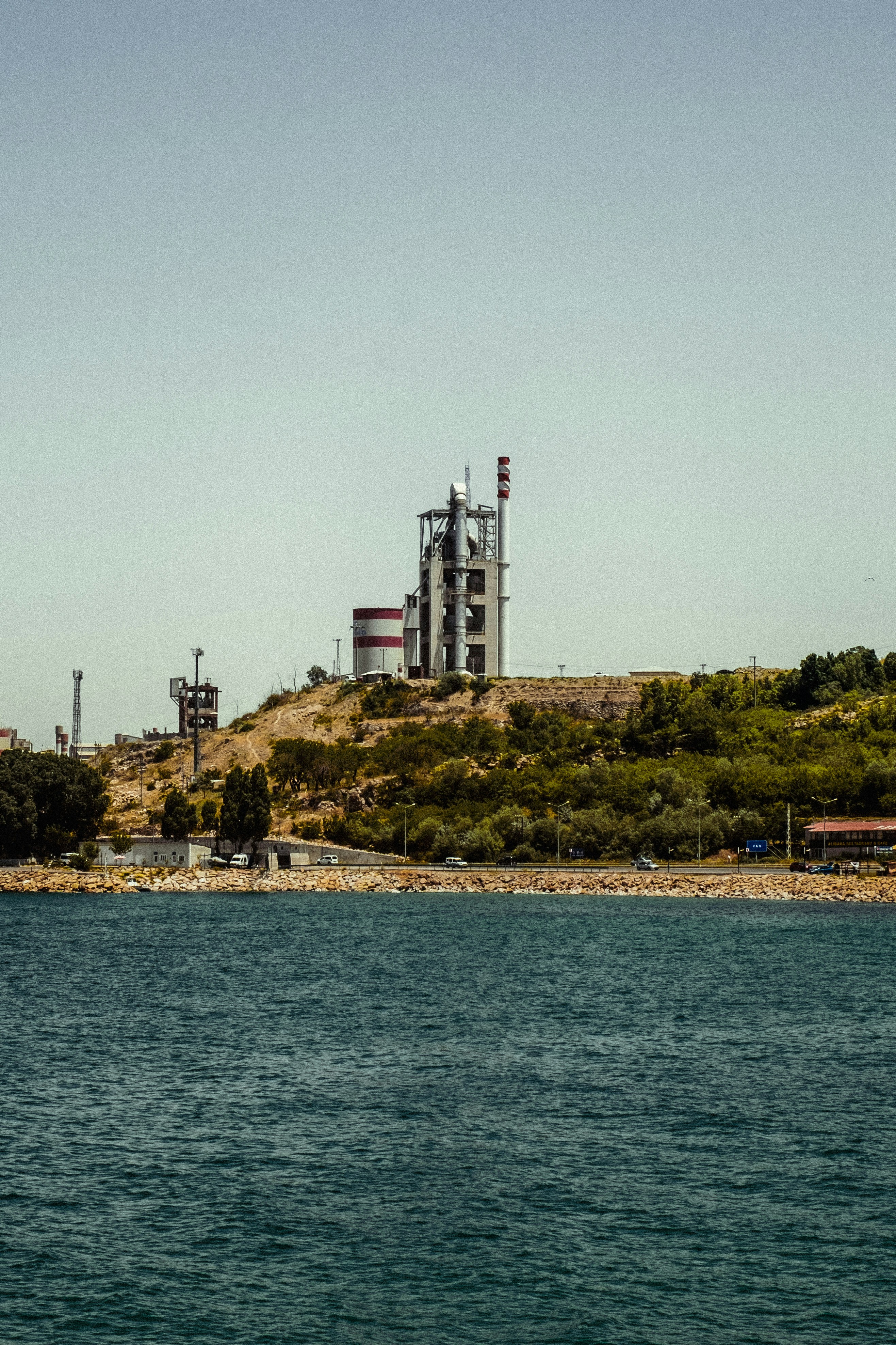 Industrial Sentinel atop the hill over a quiet shoreline
