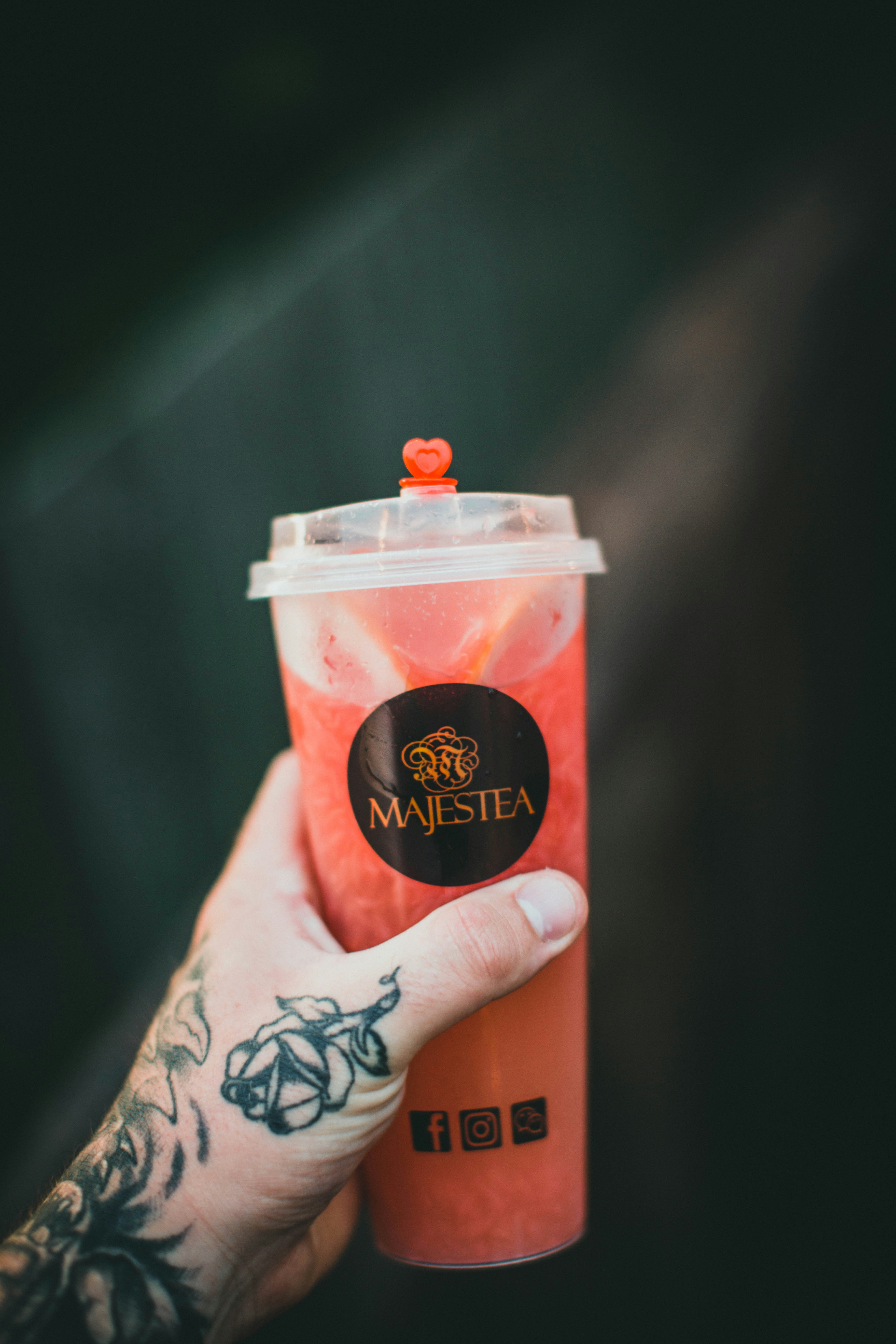 Crimson Sip: A Tattooed Grip on a Majestea Cup
