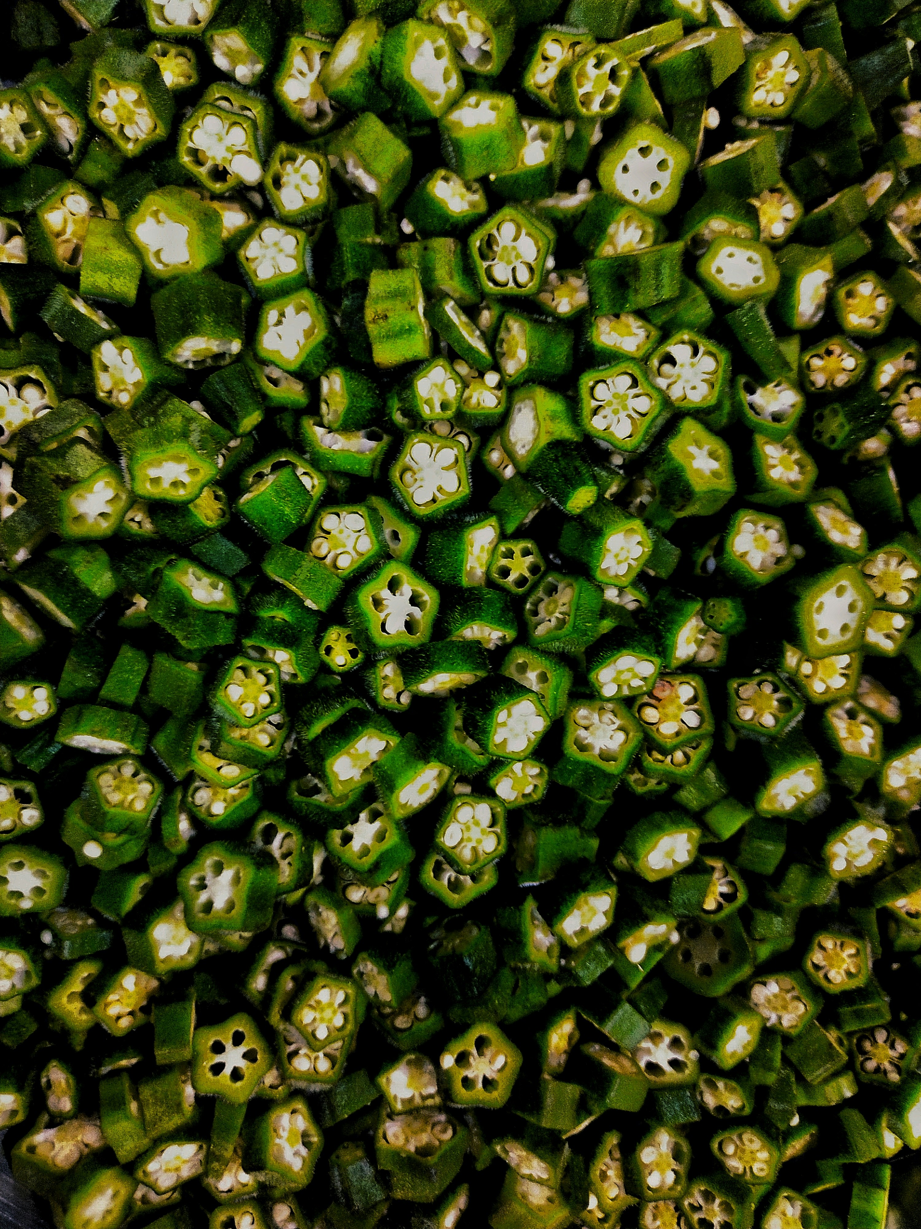 Close-up of freshly sliced okra pieces showcasing intricate patterns and vibrant green hues.