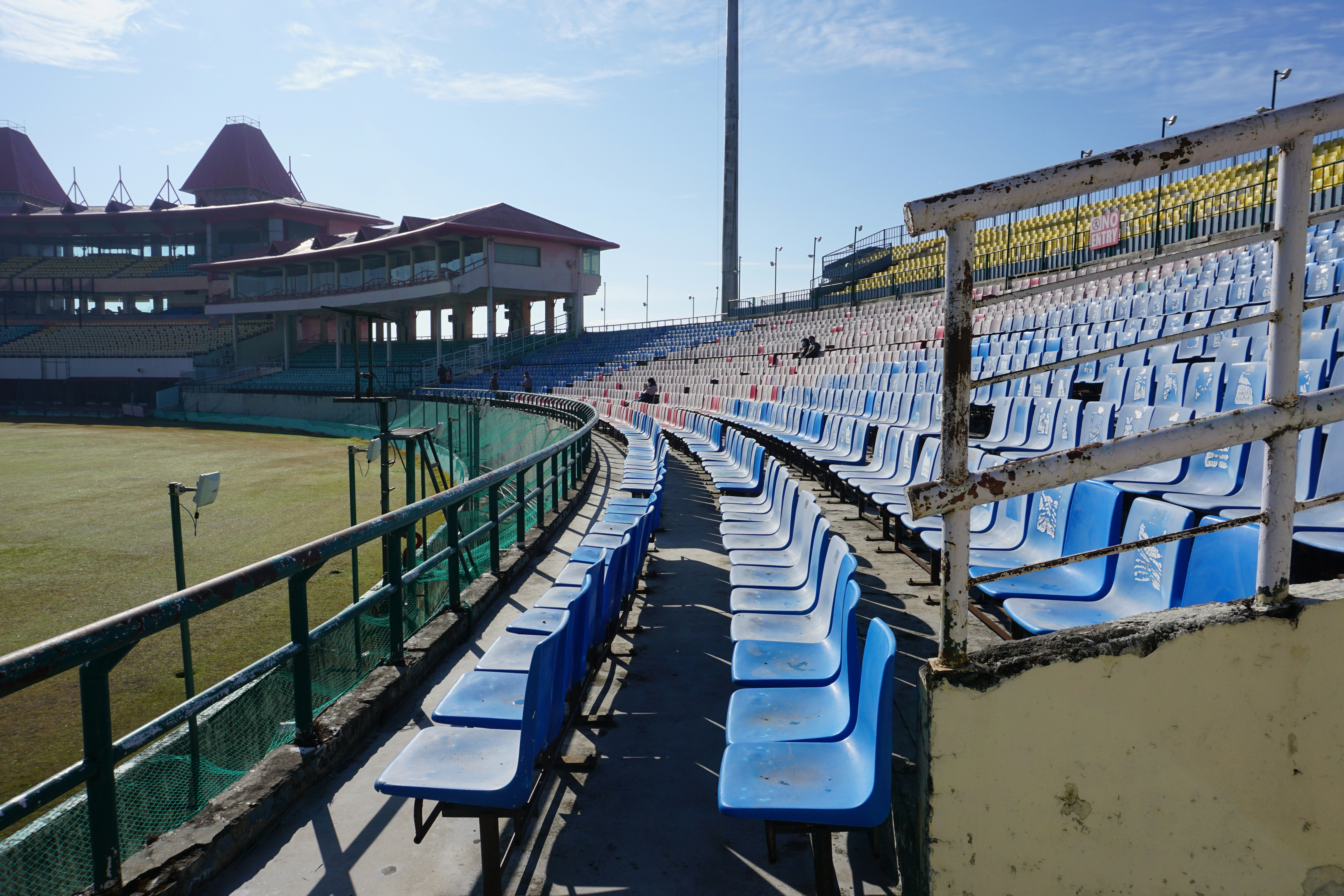 Empty stadium seats create a sense of stillness, contrasting with the vibrant colors of the surroundings. The scene captures the essence of waiting for the next event.