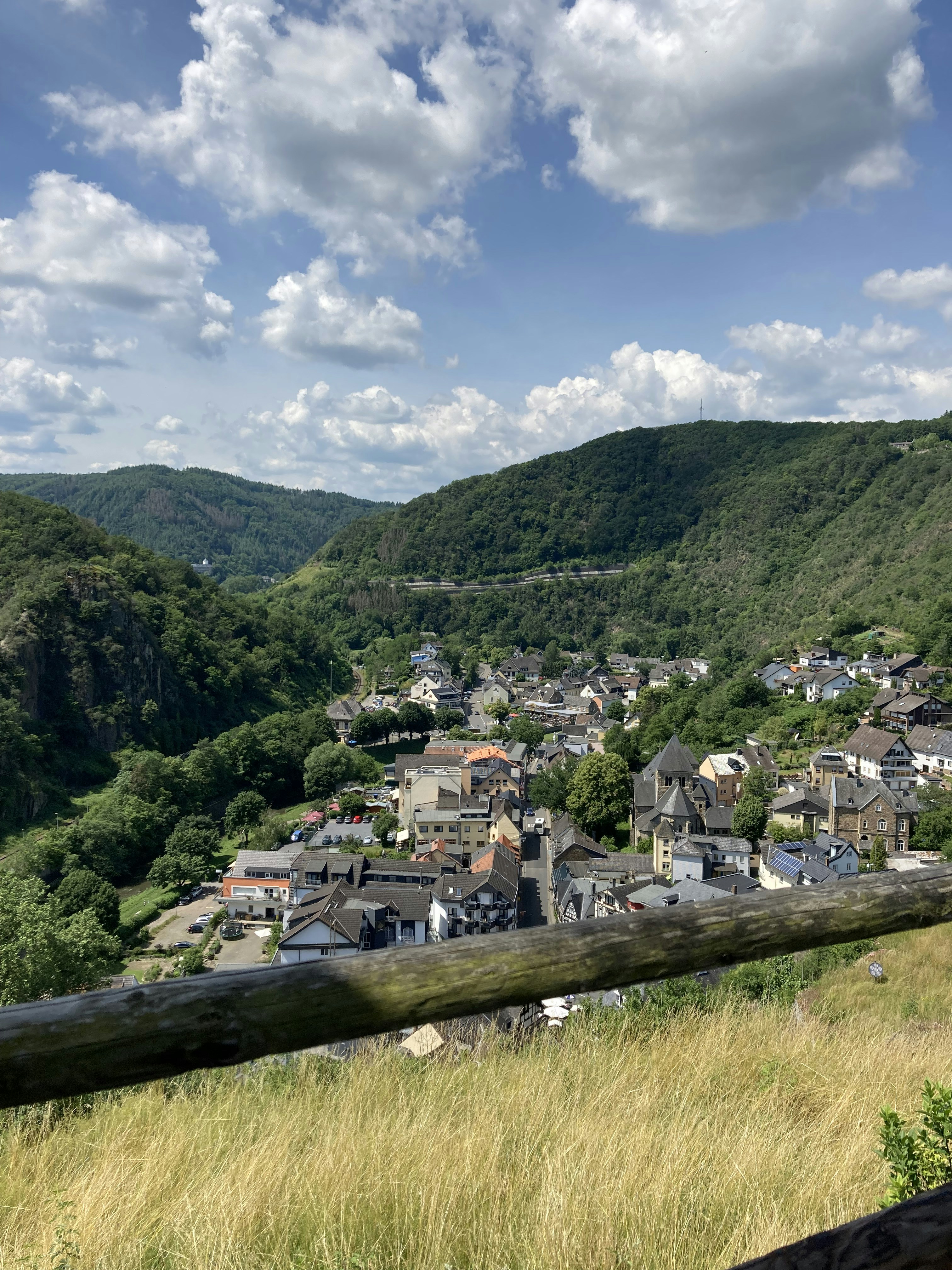 Charming village nestled in a lush valley surrounded by rolling hills and vibrant greenery. The scene captures a tranquil blend of nature and quaint architecture.