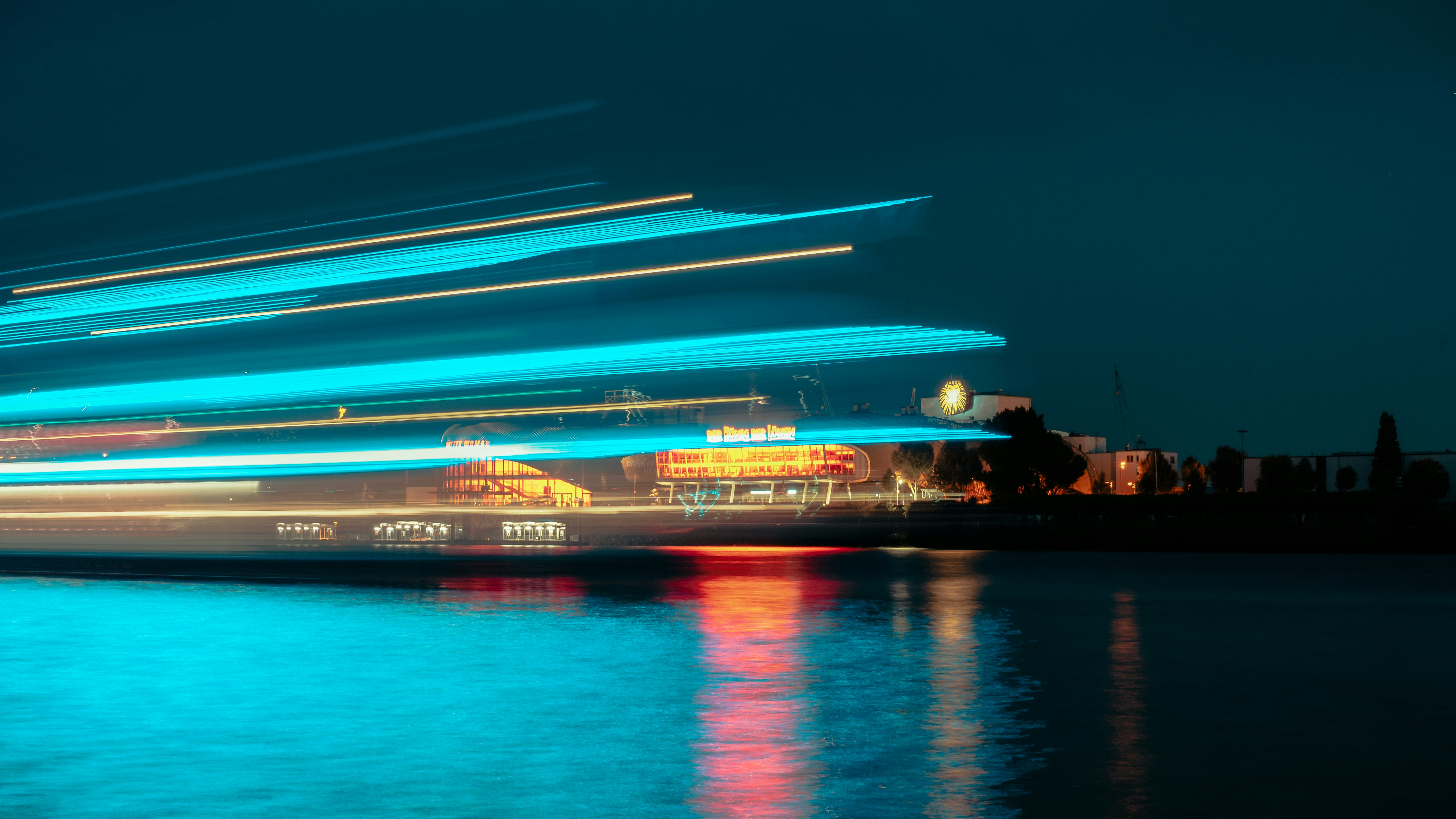 Teal and Amber Light Trails Over a Night Waterfront