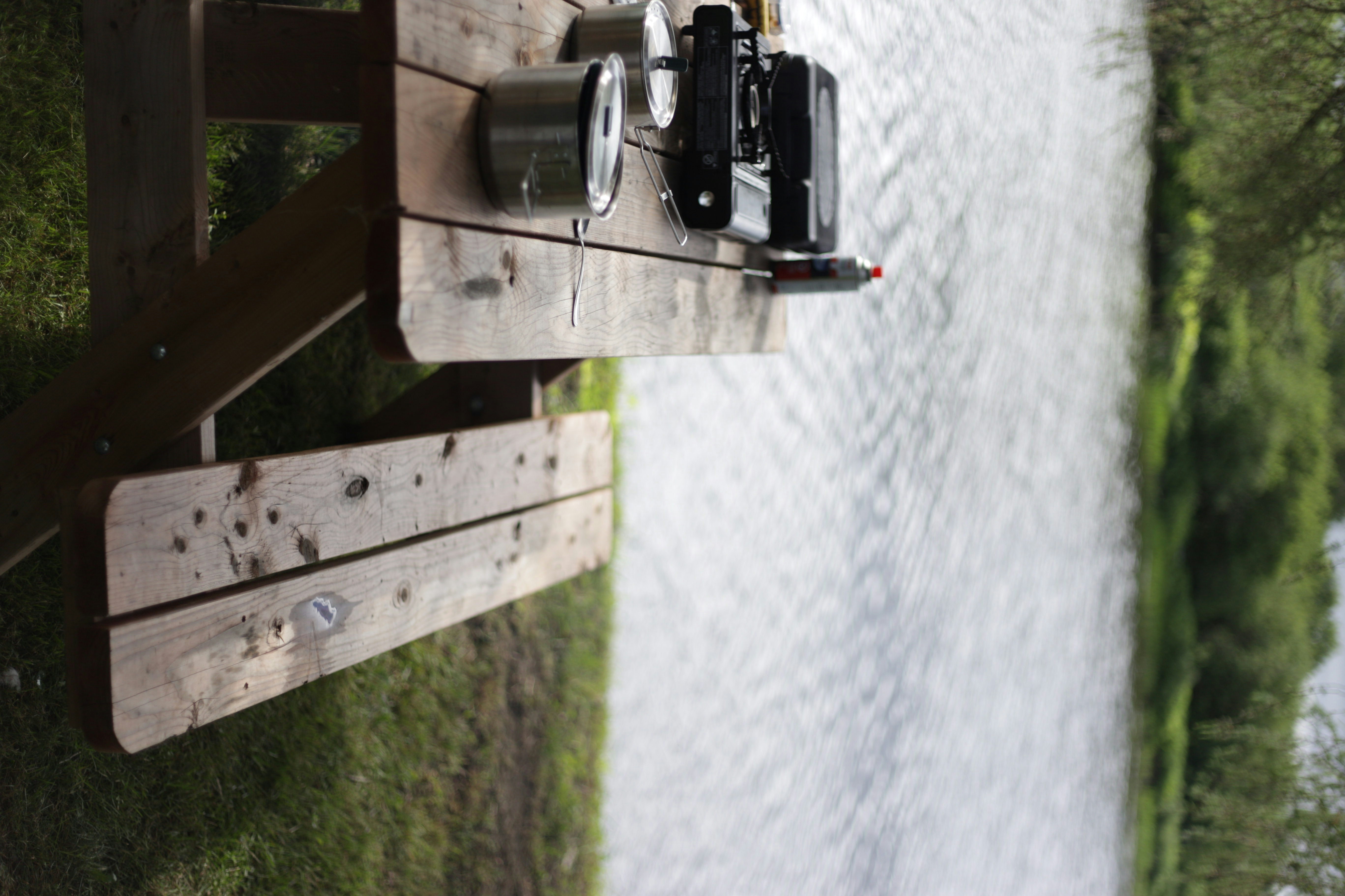Edge of Focus: A Camera Setup On Weathered Wood Beside a Calm Lakeshore