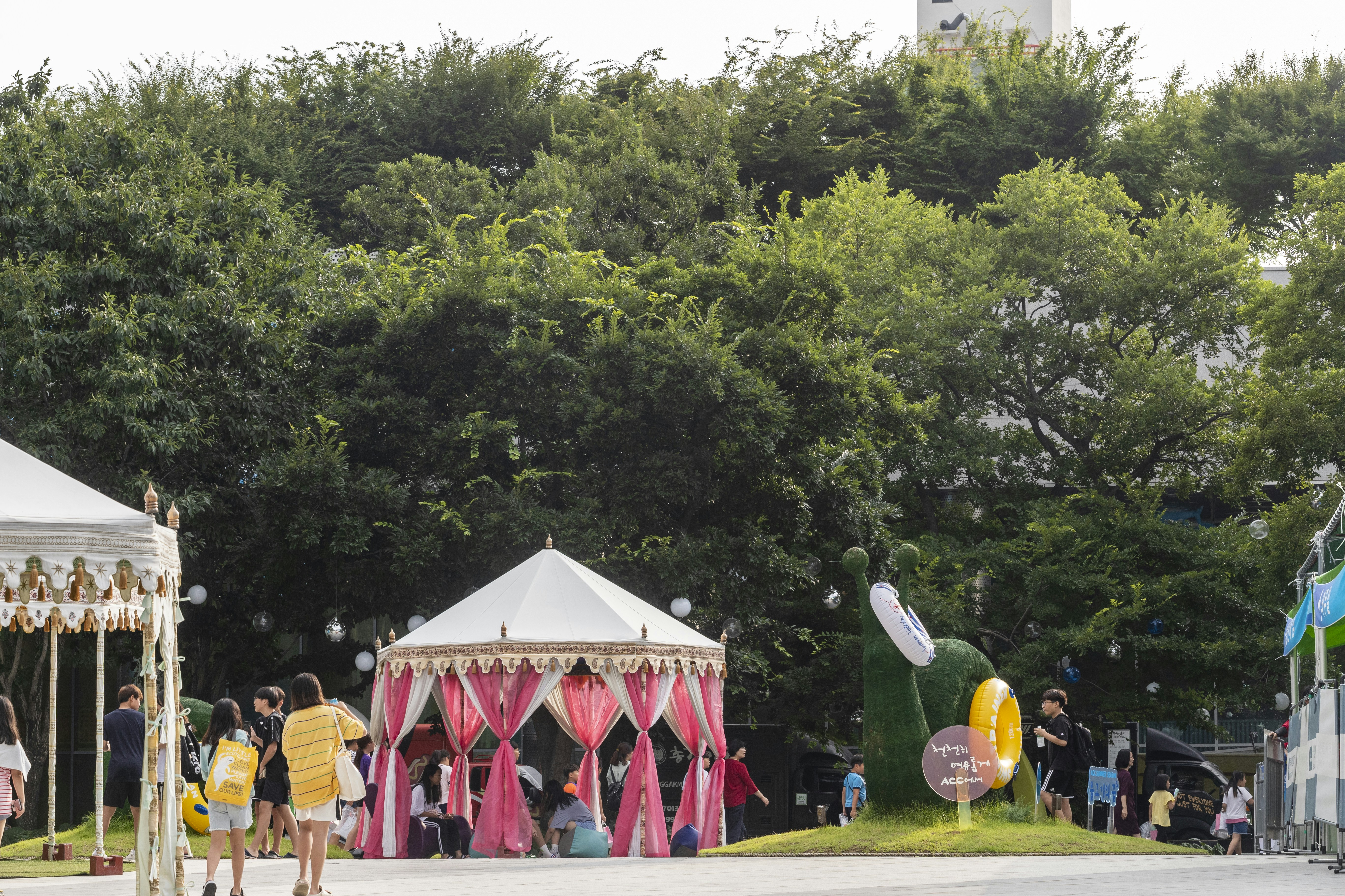Sunlit Pink Pavilion Framing a Park Festival