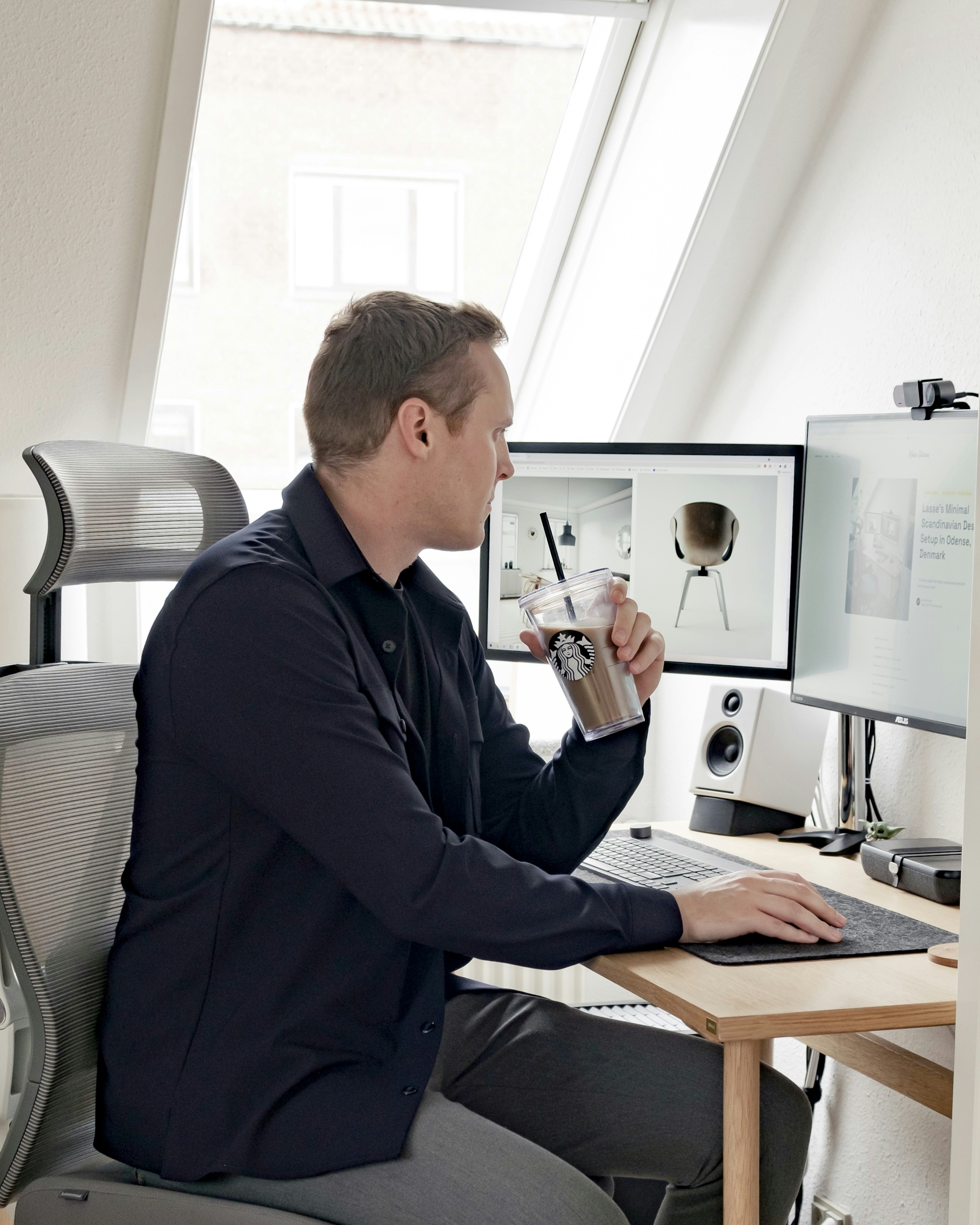 Skylit Focus: A Man, Dual Monitors, and an Iced Coffee at a Quiet Desk