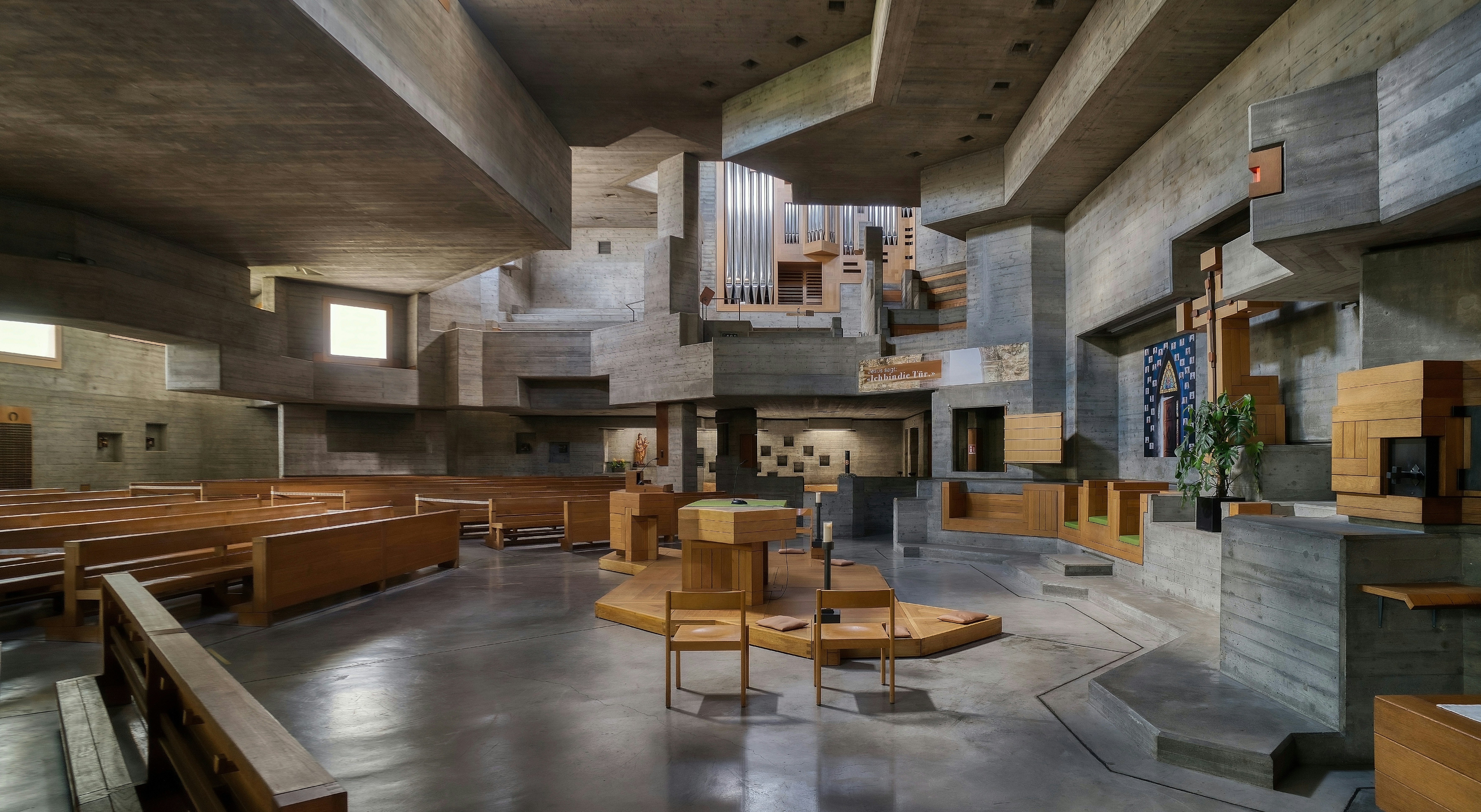 The complex of the Catholic Heiligkreuzkirche (Church of the Holy Cross)  was built in 1966-69 by Walter M. Förderer . Both the nave and the massive tower have a clear, tiered structure that make the building look like a large expressive sculpture. The column-free, gradually opening semi-circular main room is mostly indirectly lit, which makes it seem like a rock cave
Source : Chur Tourismus