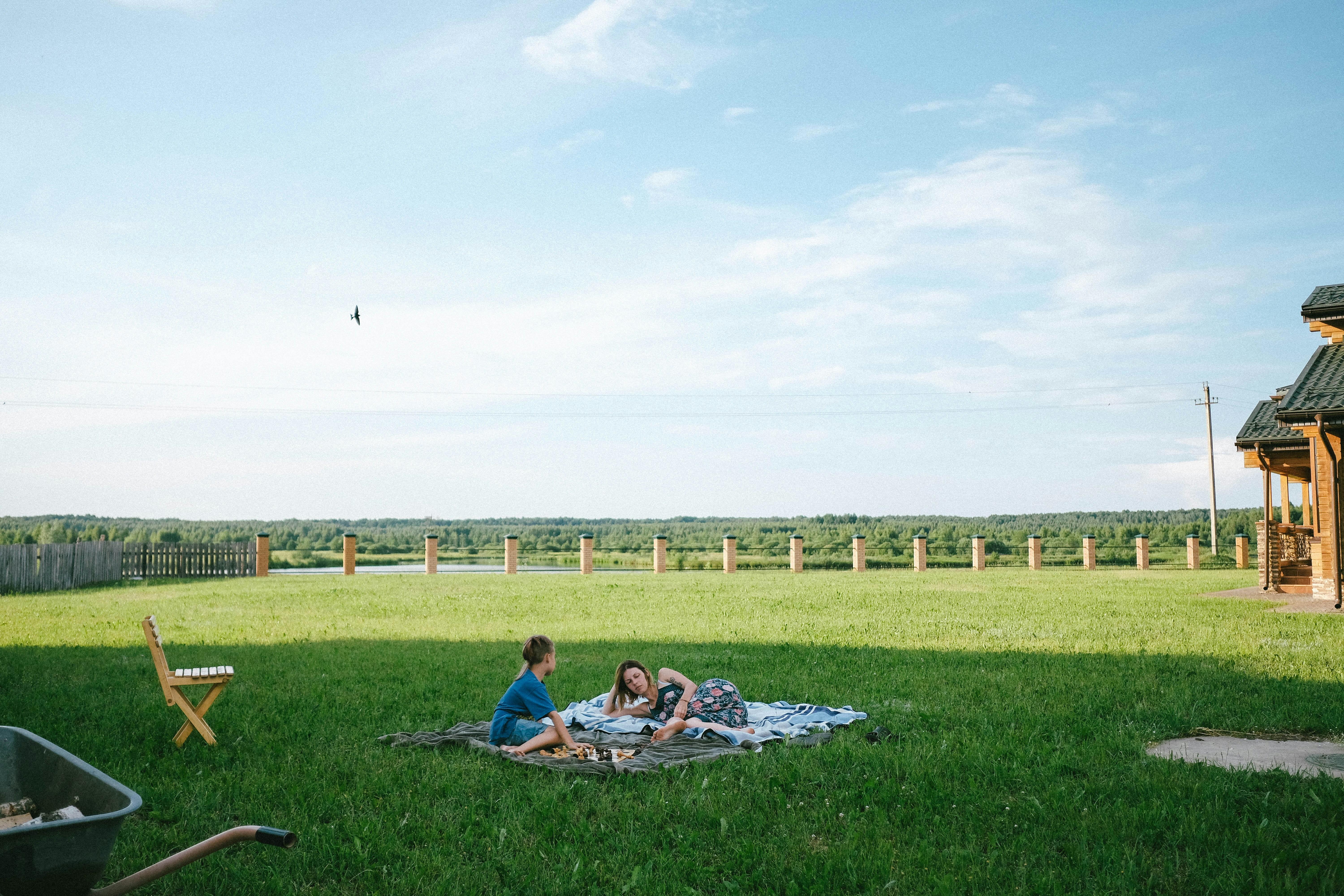 Children enjoying a picnic on a grassy field under a clear blue sky.
