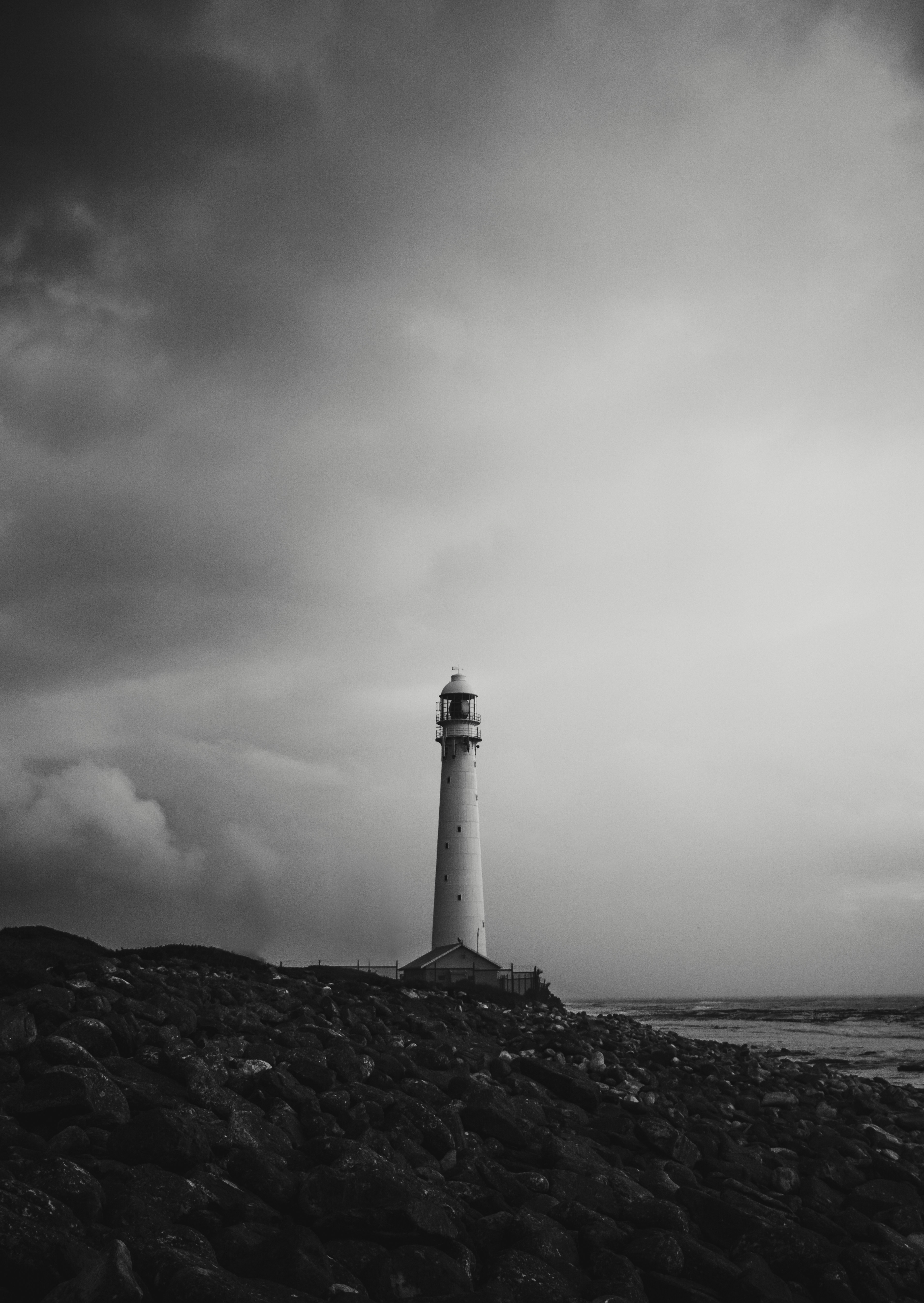 White and black lighthouse near body of water under cloudy sky photo ...