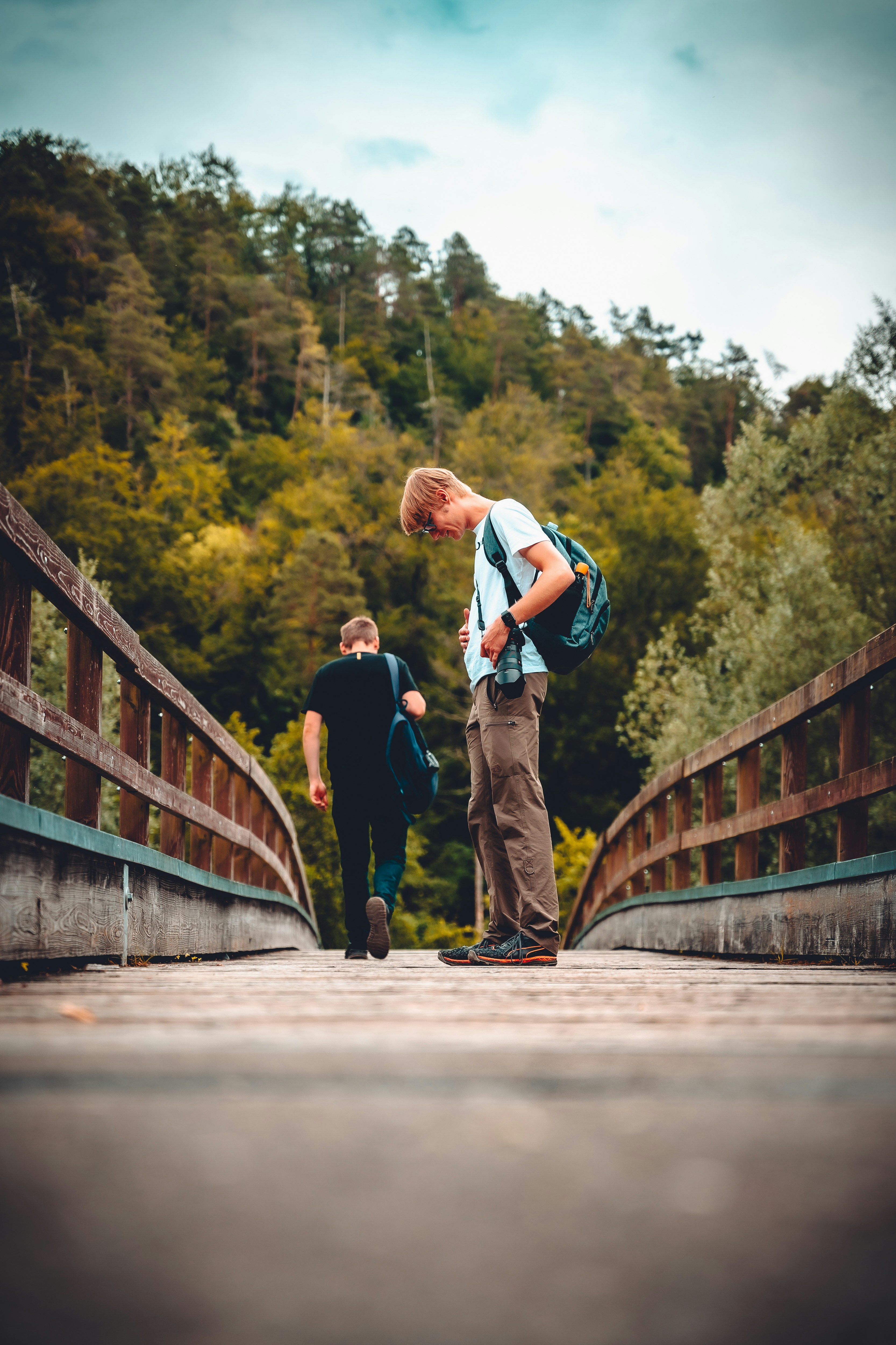 Two Backpackers Pause on a Weathered Forest Bridge