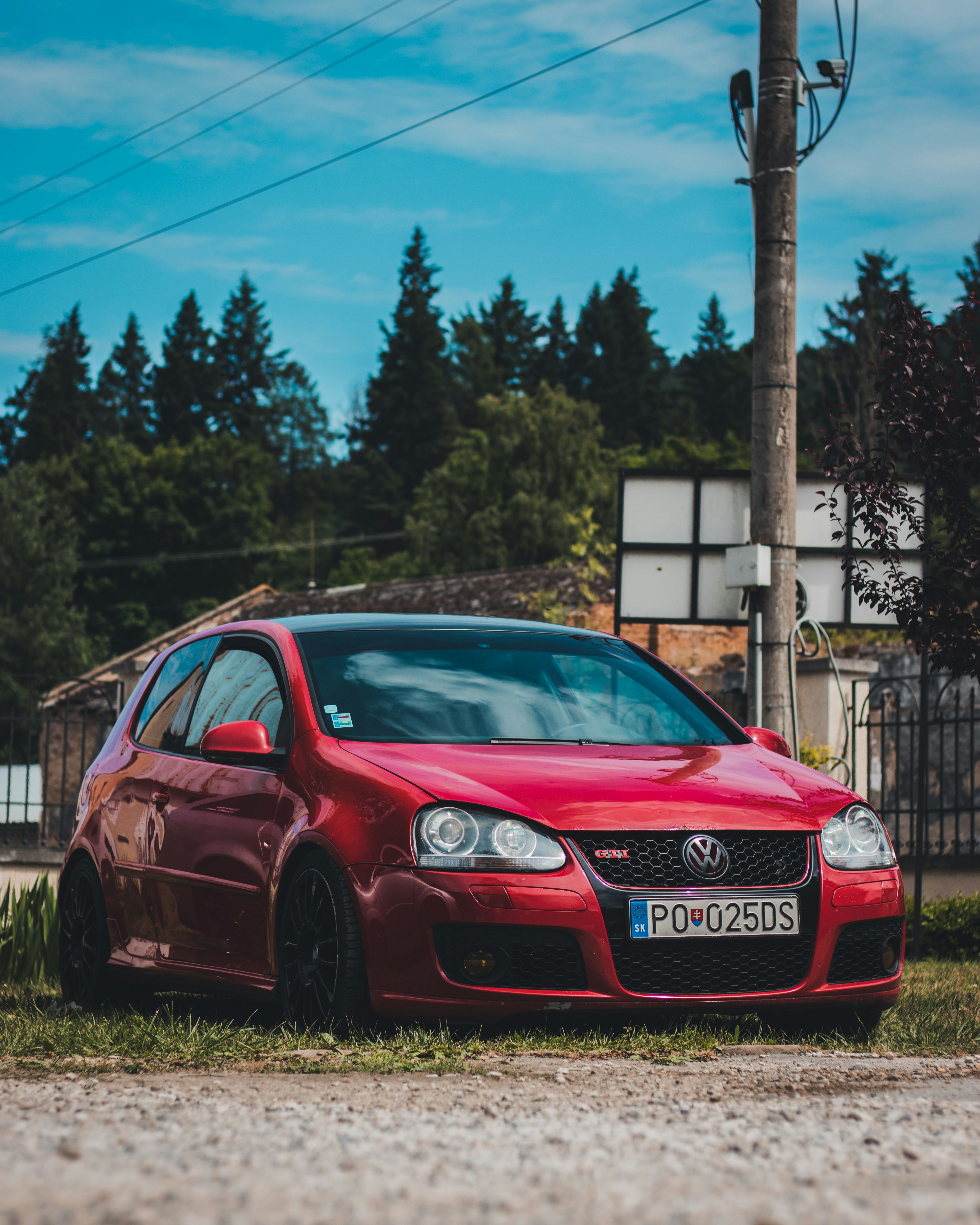 Red Volkswagen Golf Roaming by a Rural Utility Pole