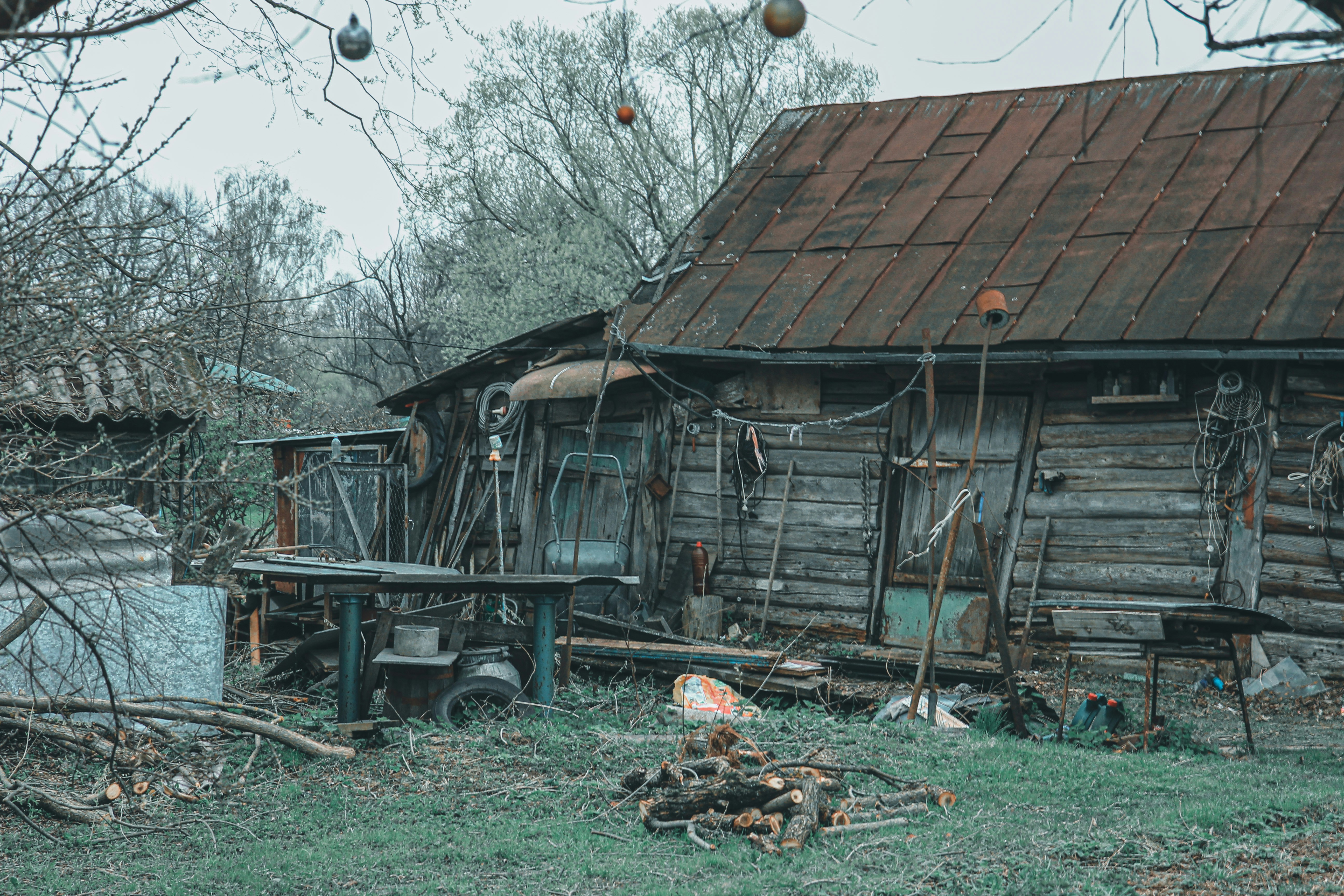 Weathered wooden cabin surrounded by scattered tools and remnants of nature, evoking a sense of nostalgia and history.
