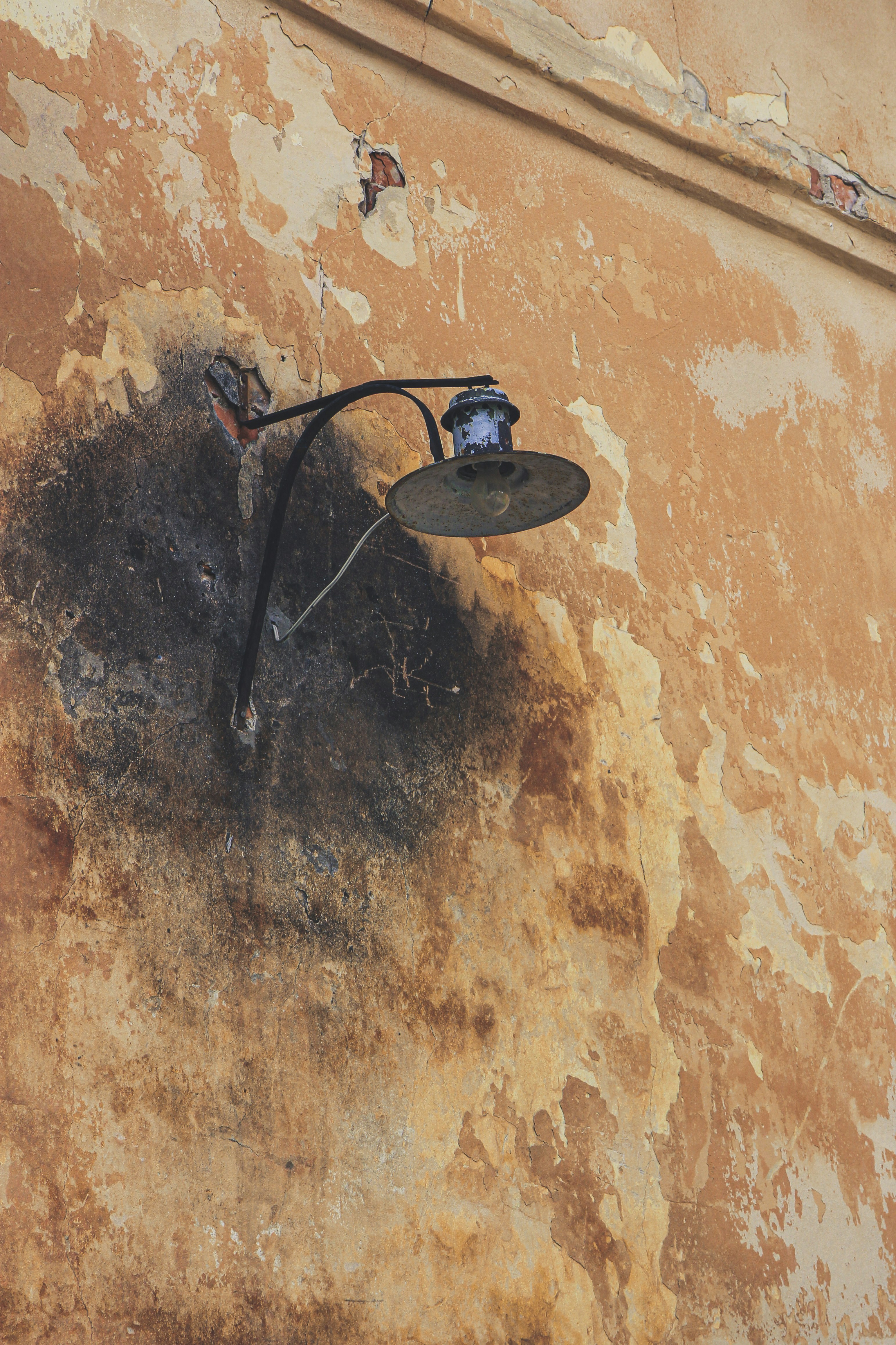 Patina Lamp on a Peeling Wall: Time's Quiet Fixture