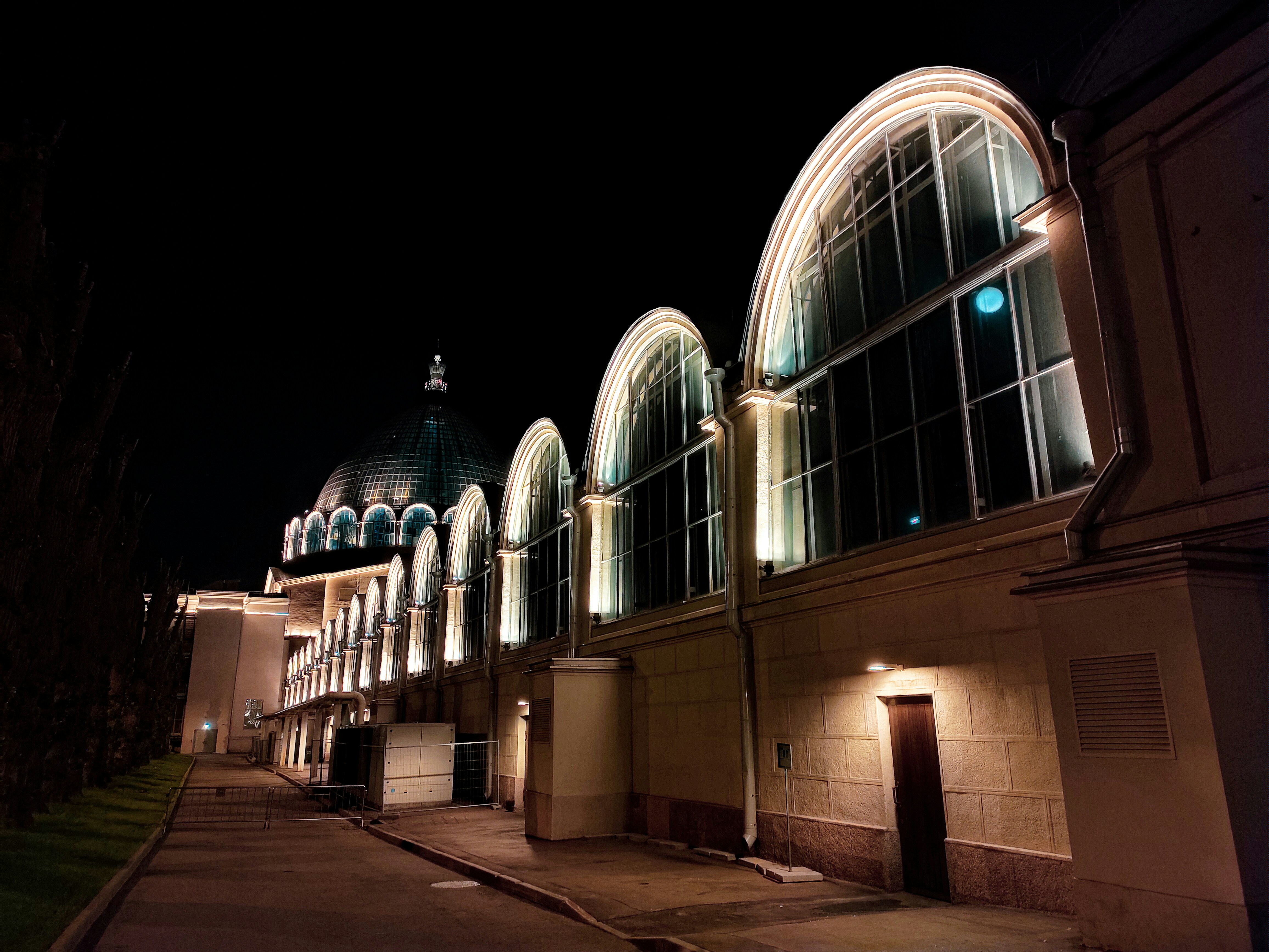 Elegant building facade featuring illuminated arches, showcasing a blend of modern and classical design elements at night.