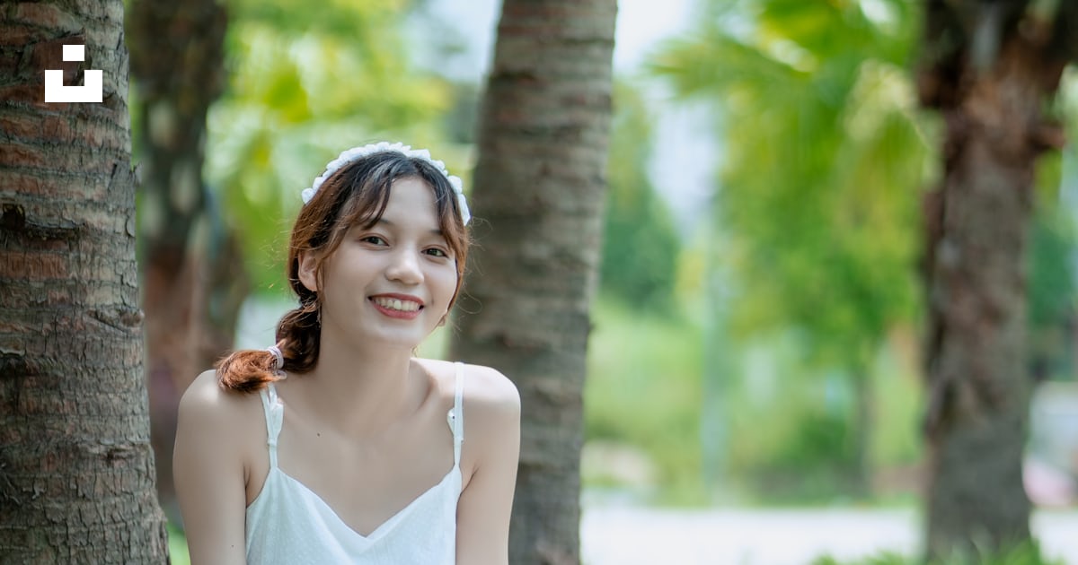 나무에 기대어 있는 흰색 스파게티 스트랩 드레스를 입은 여자 사진 Unsplash의 무료 야외 이미지