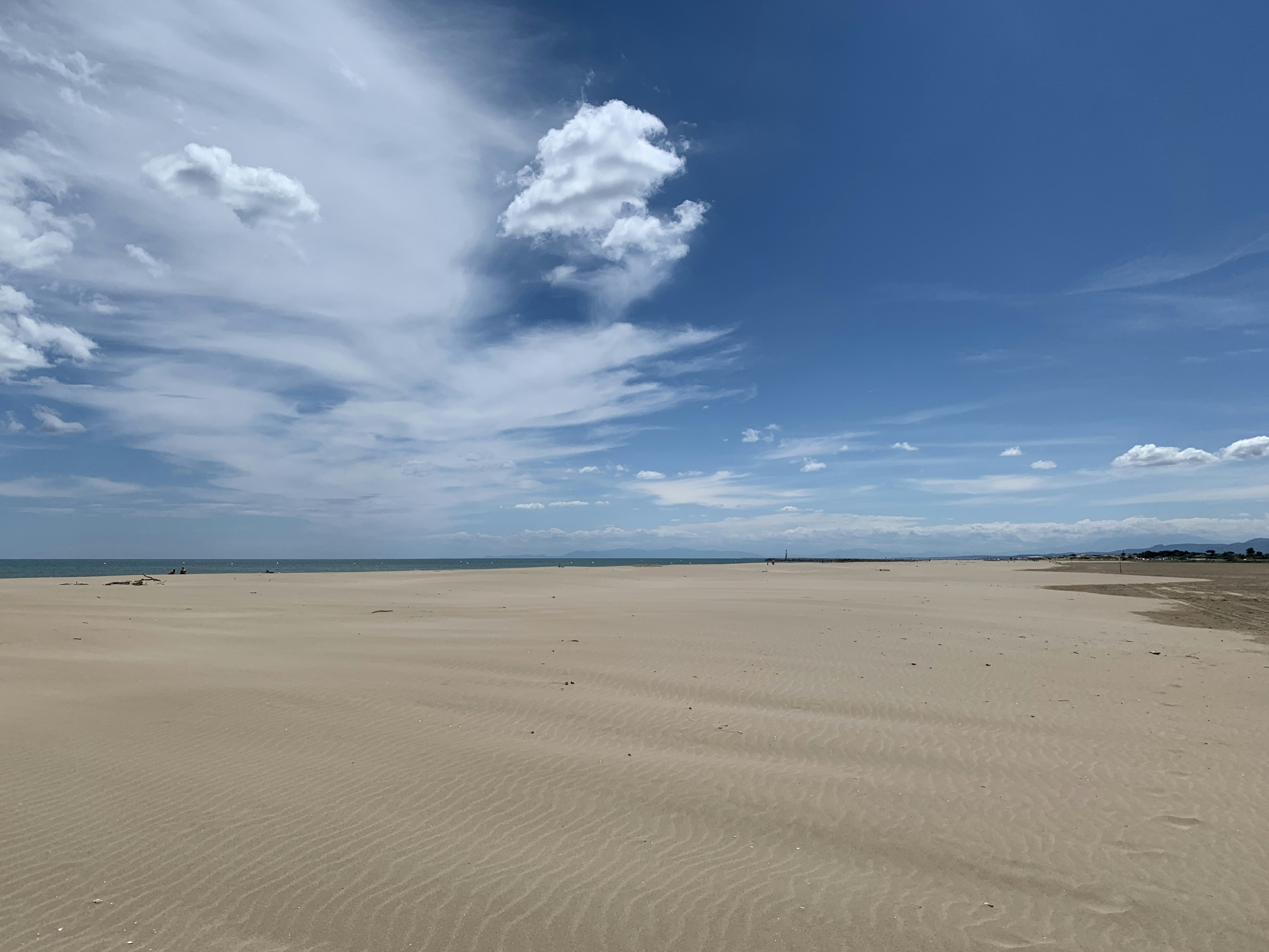 Vast expanse of sandy beach meeting a vibrant sky filled with clouds, creating a serene coastal atmosphere.