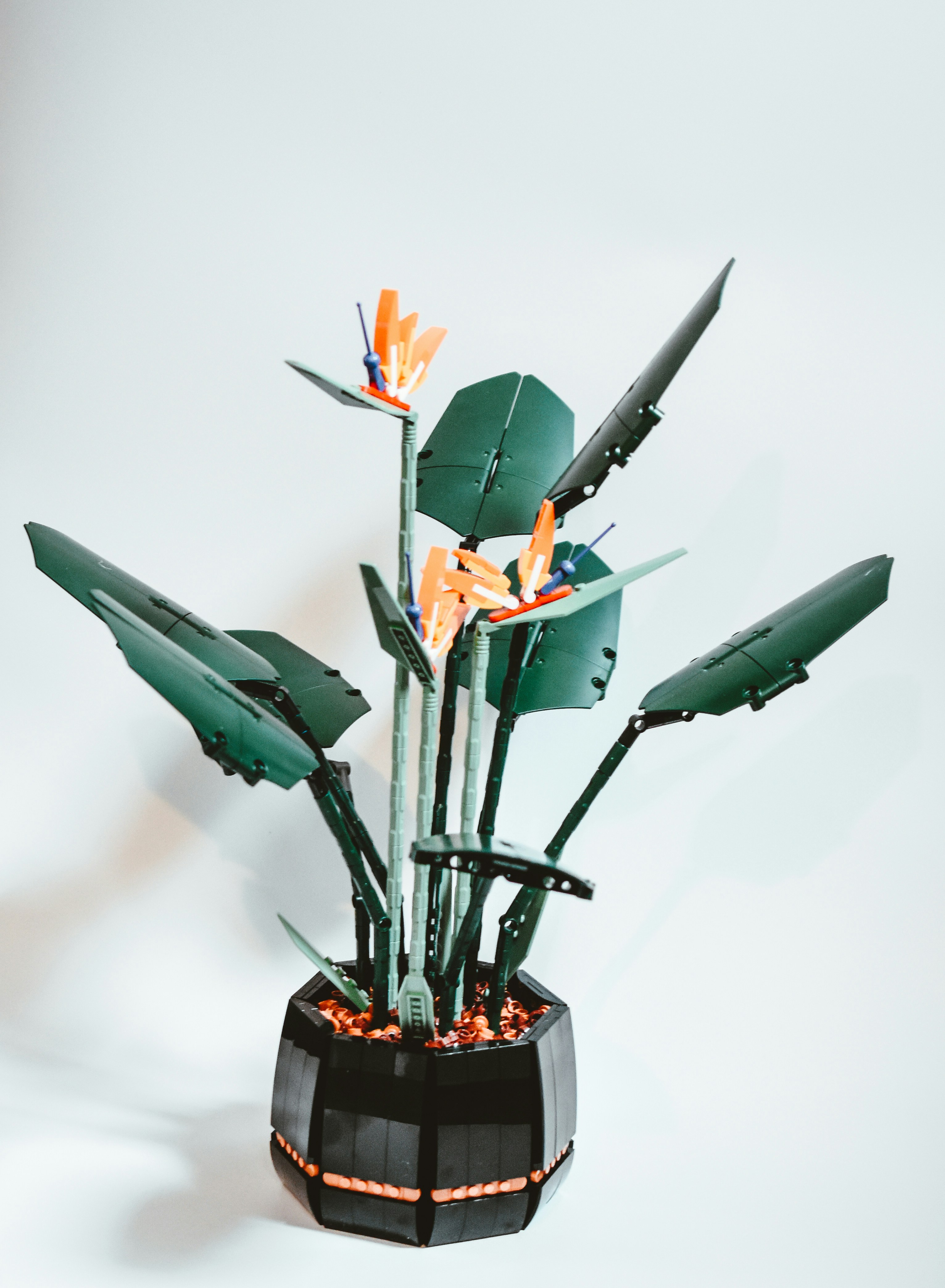 Colorful artificial flowers crafted from plastic components arranged in a sleek black pot, showcasing a blend of creativity and design.