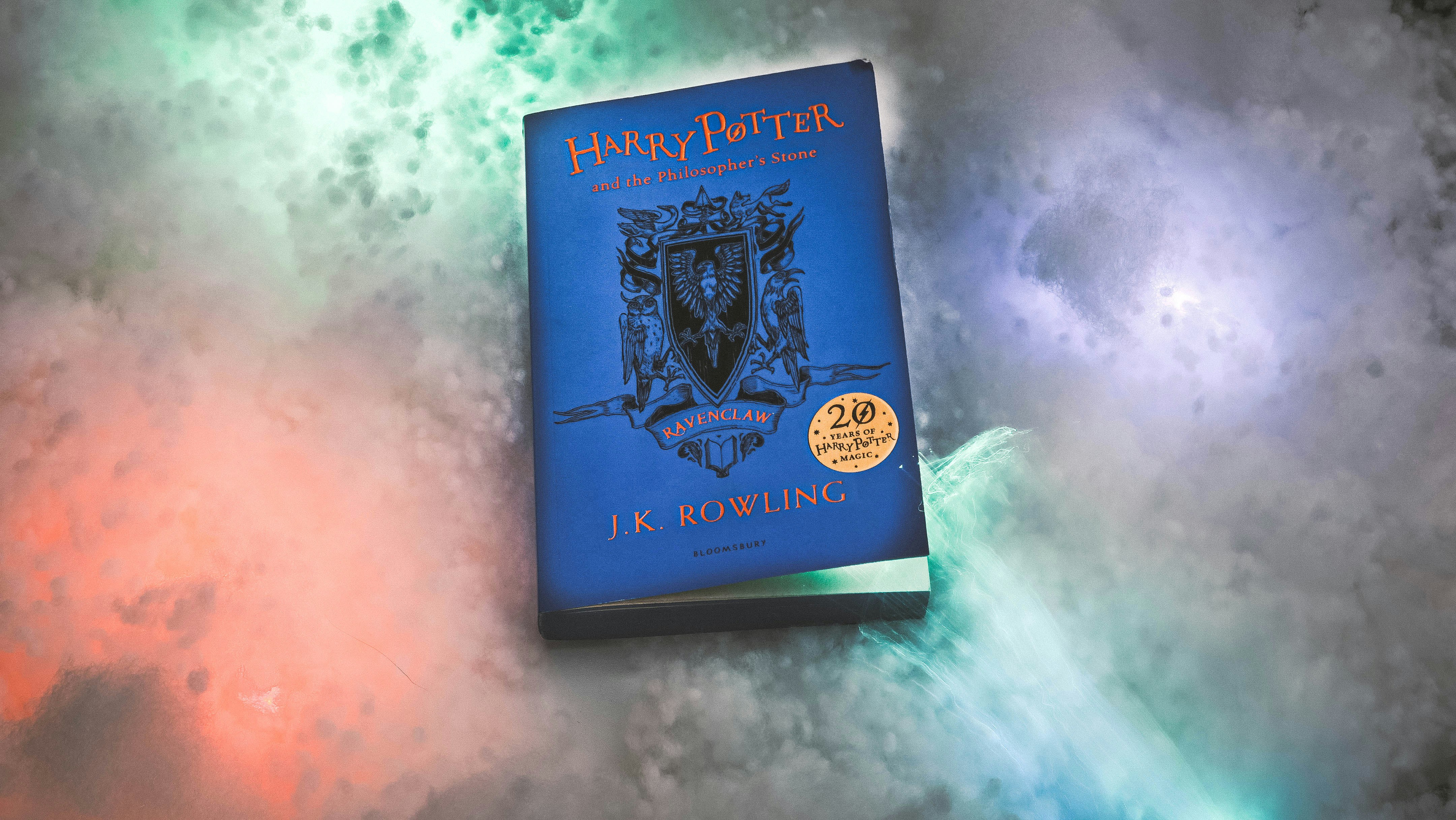 The iconic cover of 'Harry Potter and the Philosopher's Stone' featuring a vibrant blue design with intricate details and a golden anniversary badge.