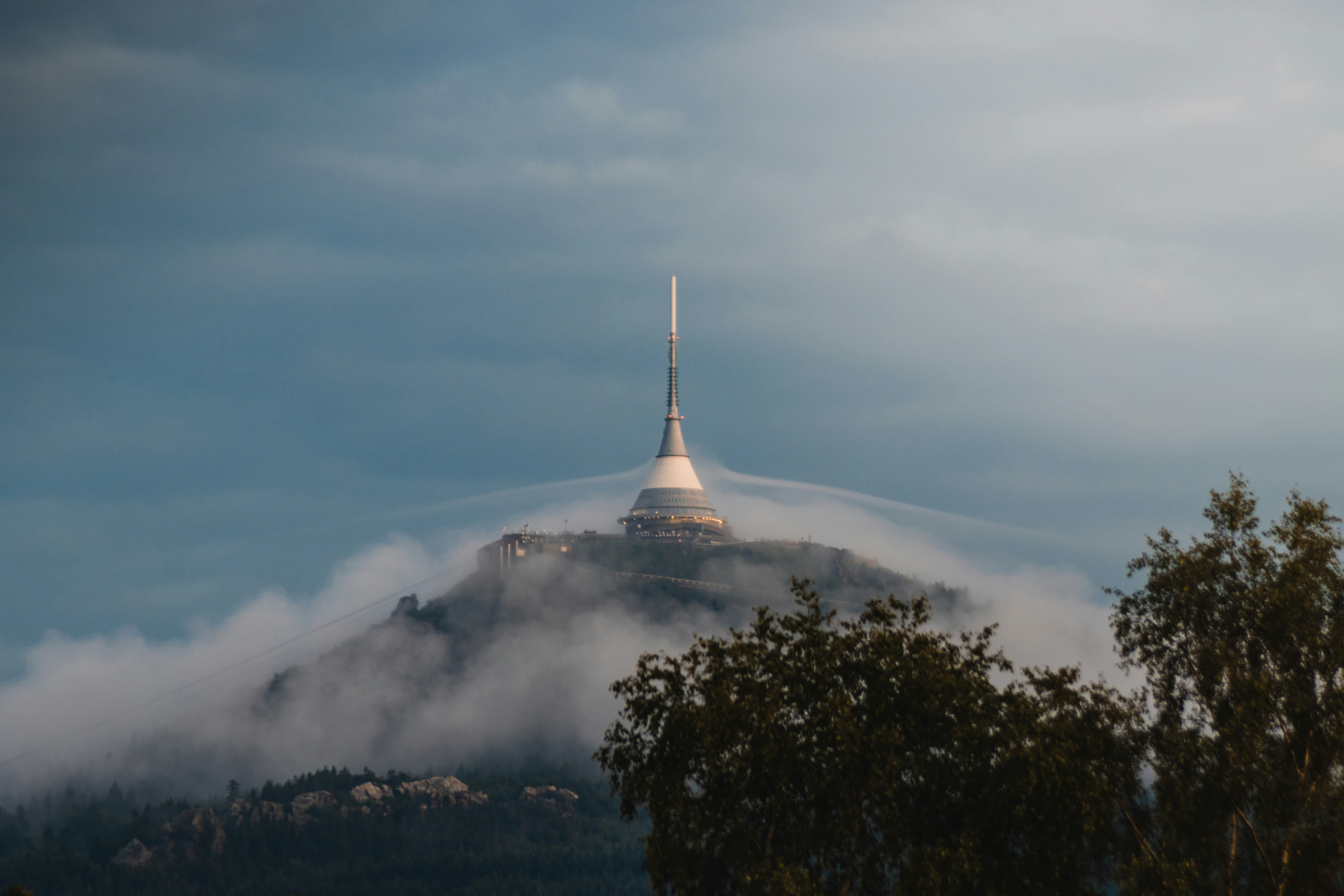 The Jested tower is photographed from a distance with a telephoto lens, while a mysterious fog spreads beneath it