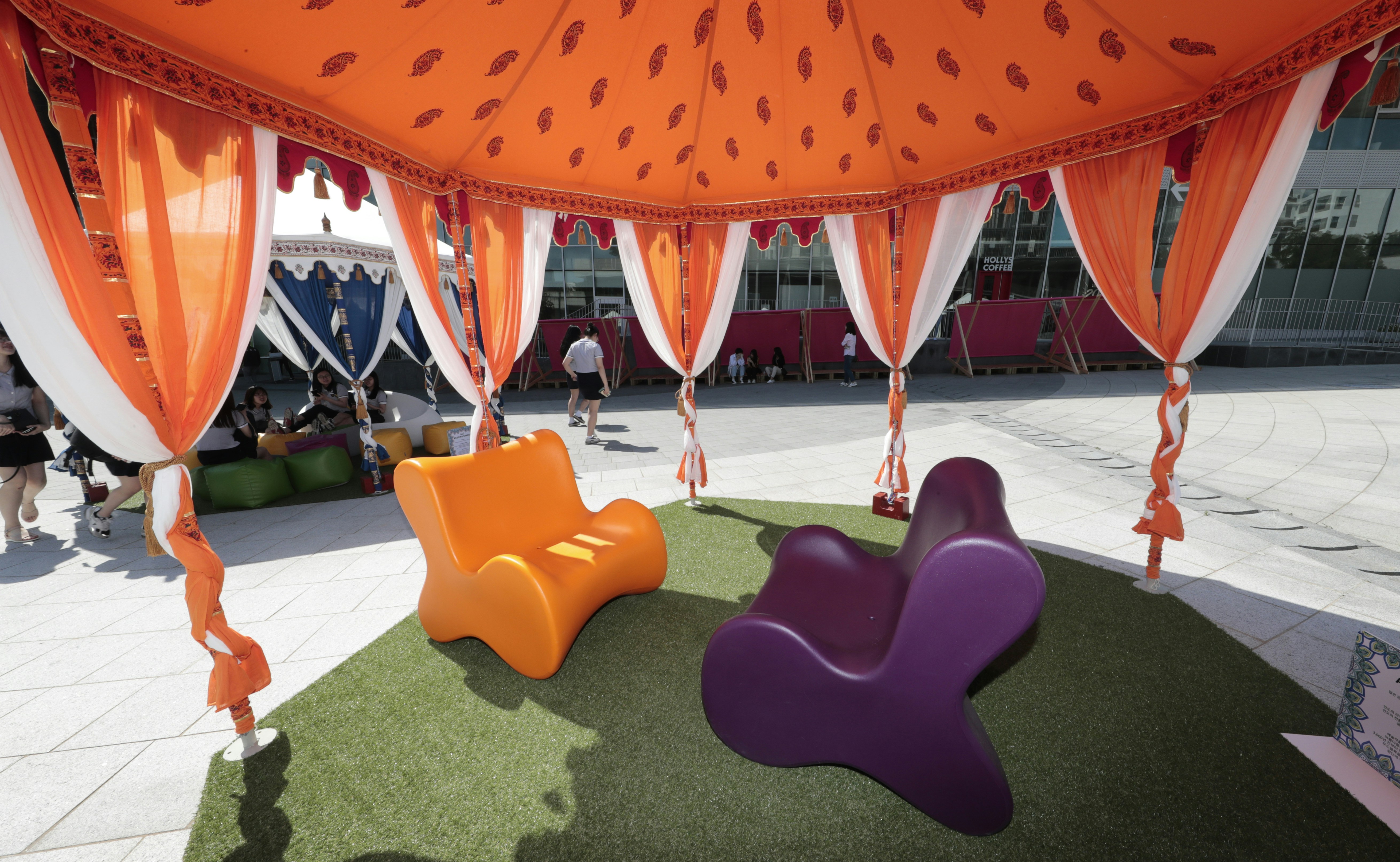 Under the Tangerine Canopy, a Purple Lounge Chair Anchors a Sunlit Courtyard
