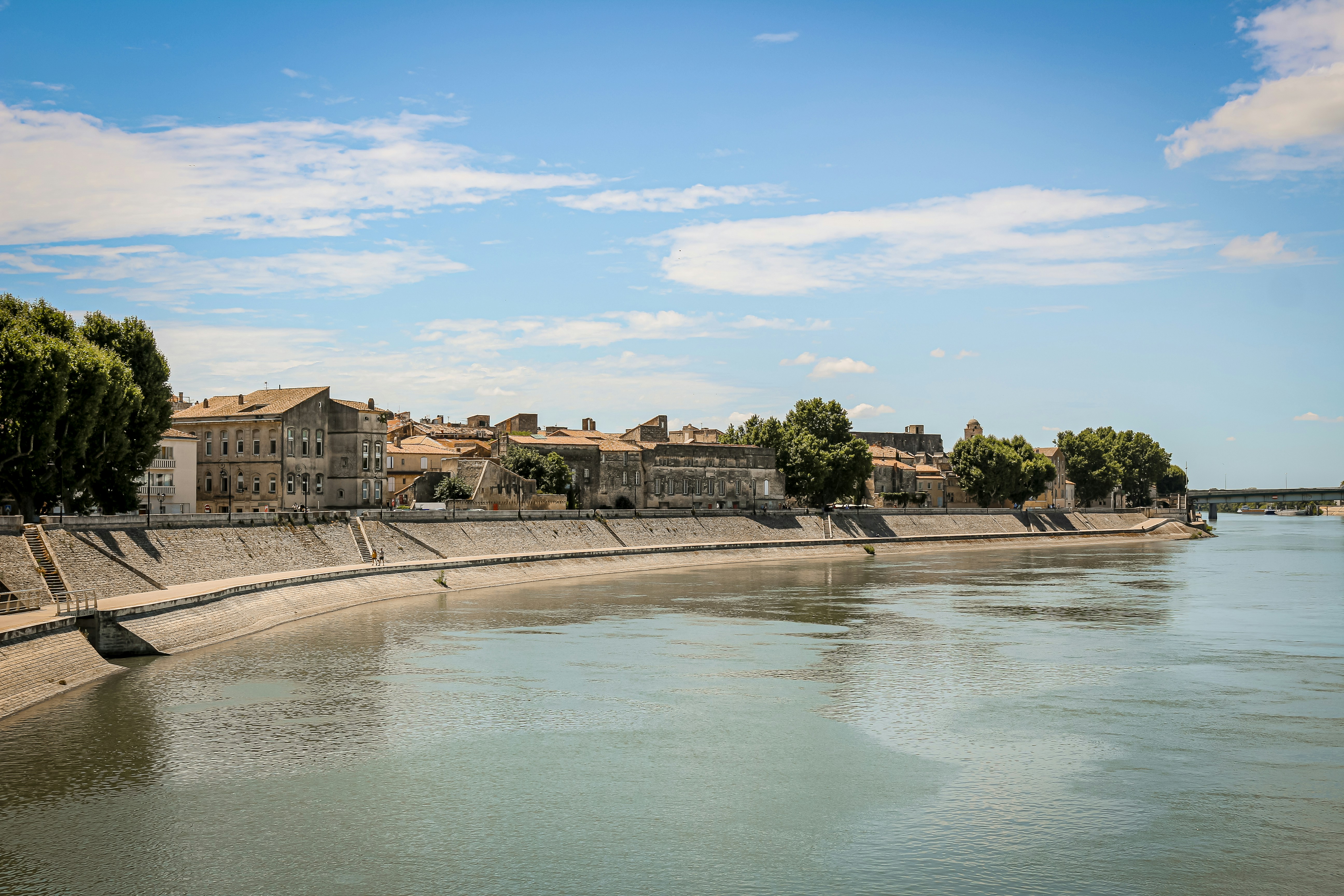 Historic brown buildings line a riverside under a vibrant blue sky.