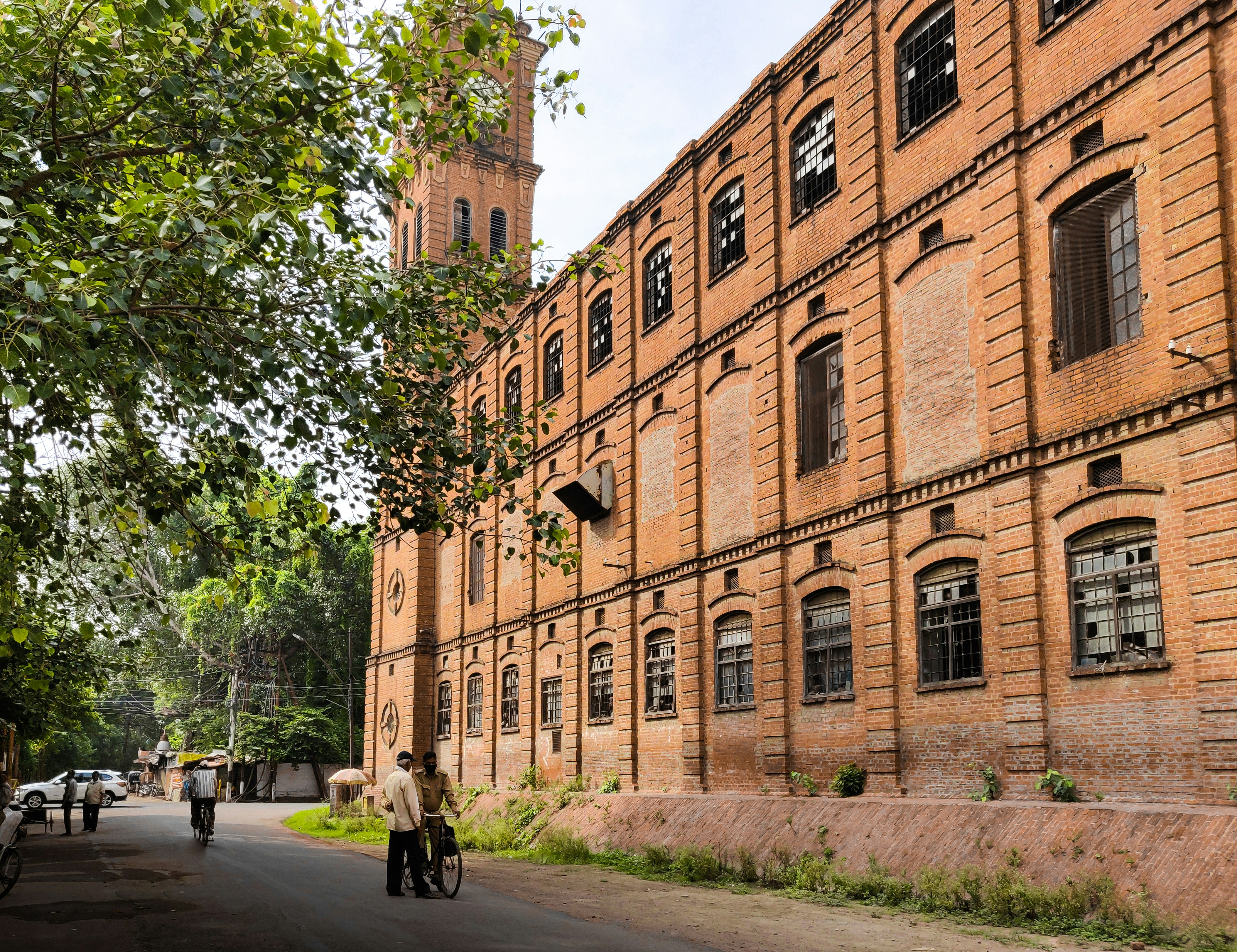 police man on a cycle near a building | people walking on sidewalk near brown concrete building during daytime