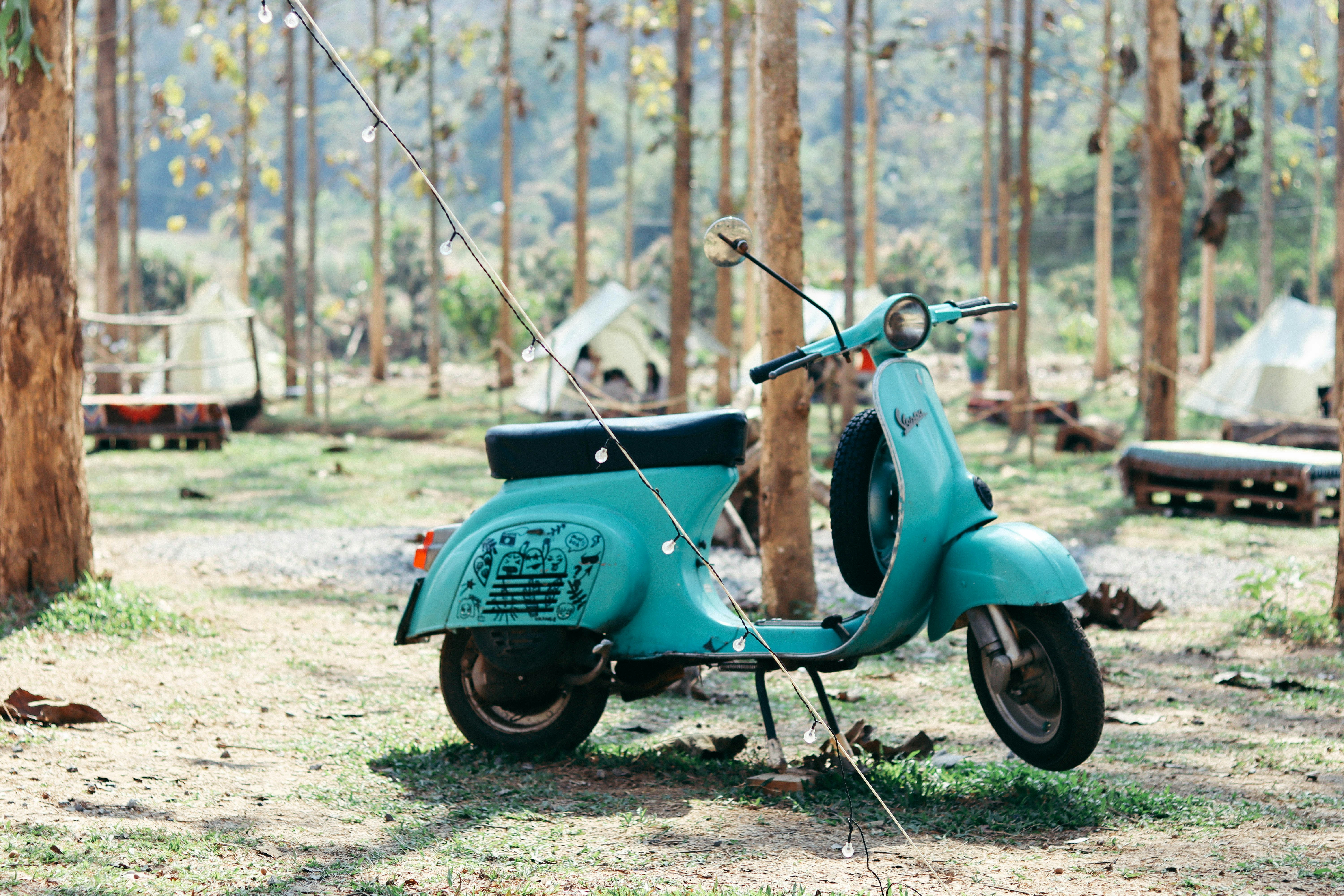 blue and black motor scooter parked on green grass field during daytime