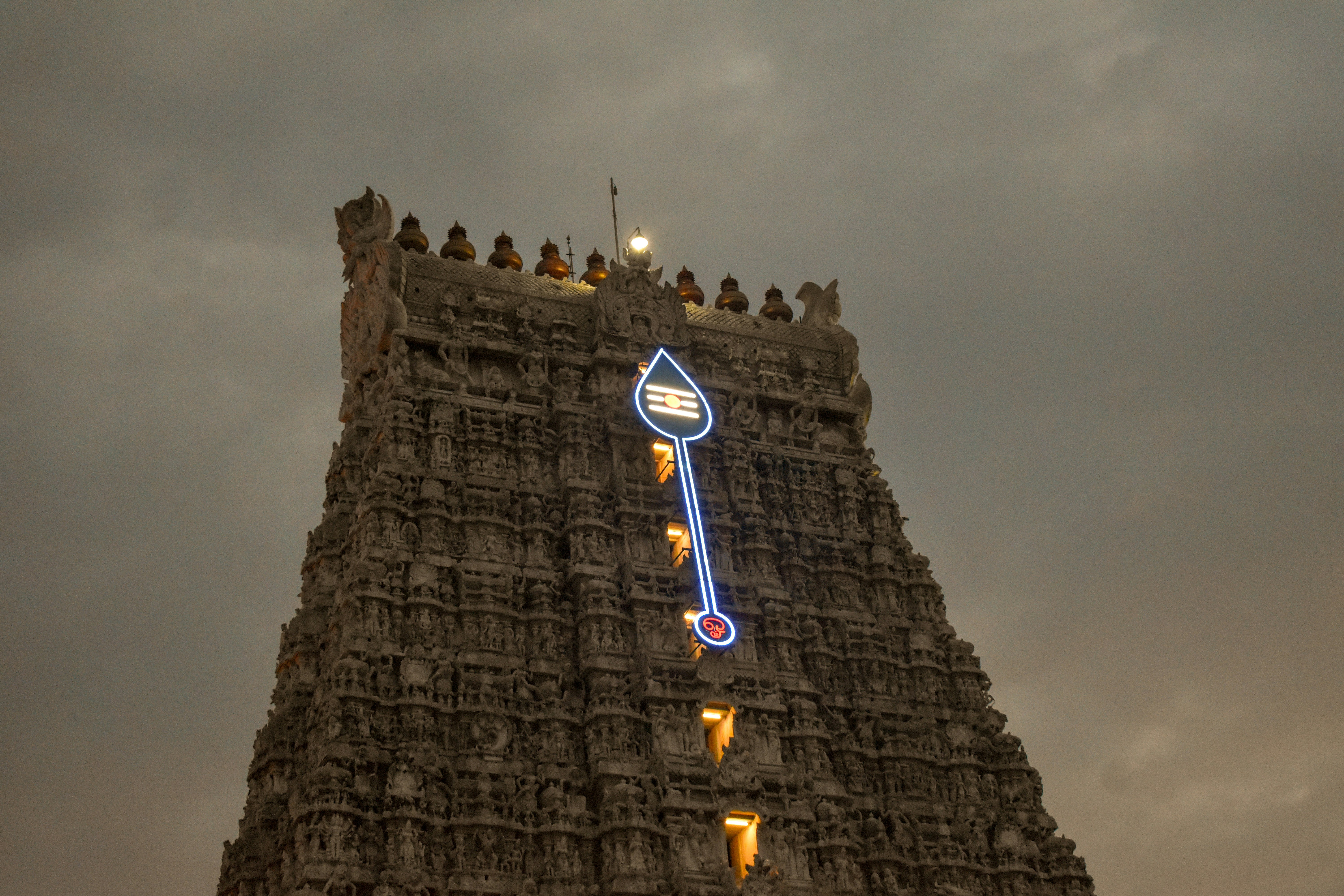 A tall structure called Gopuram in Hindu Temples. | lighted street light on top of brown concrete building