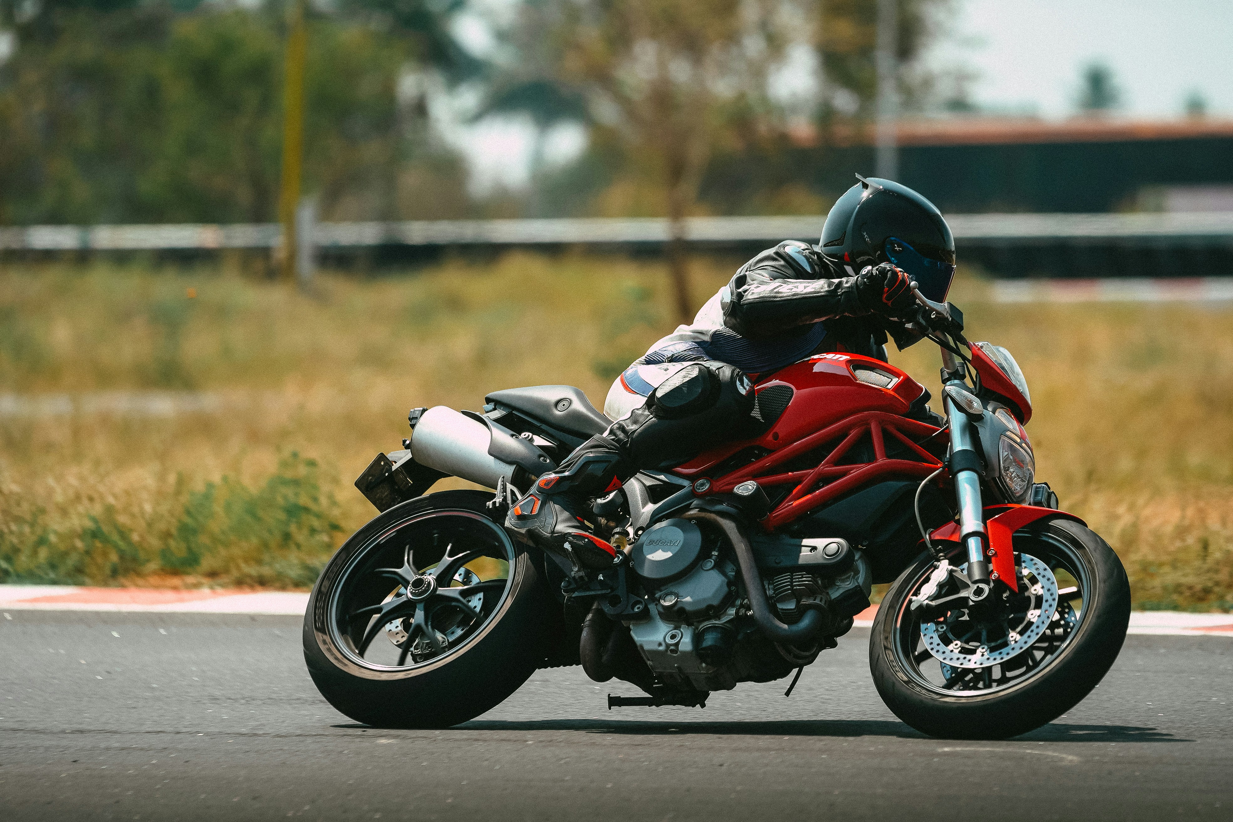 Man in orange and black motorcycle suit riding motorcycle on road ...