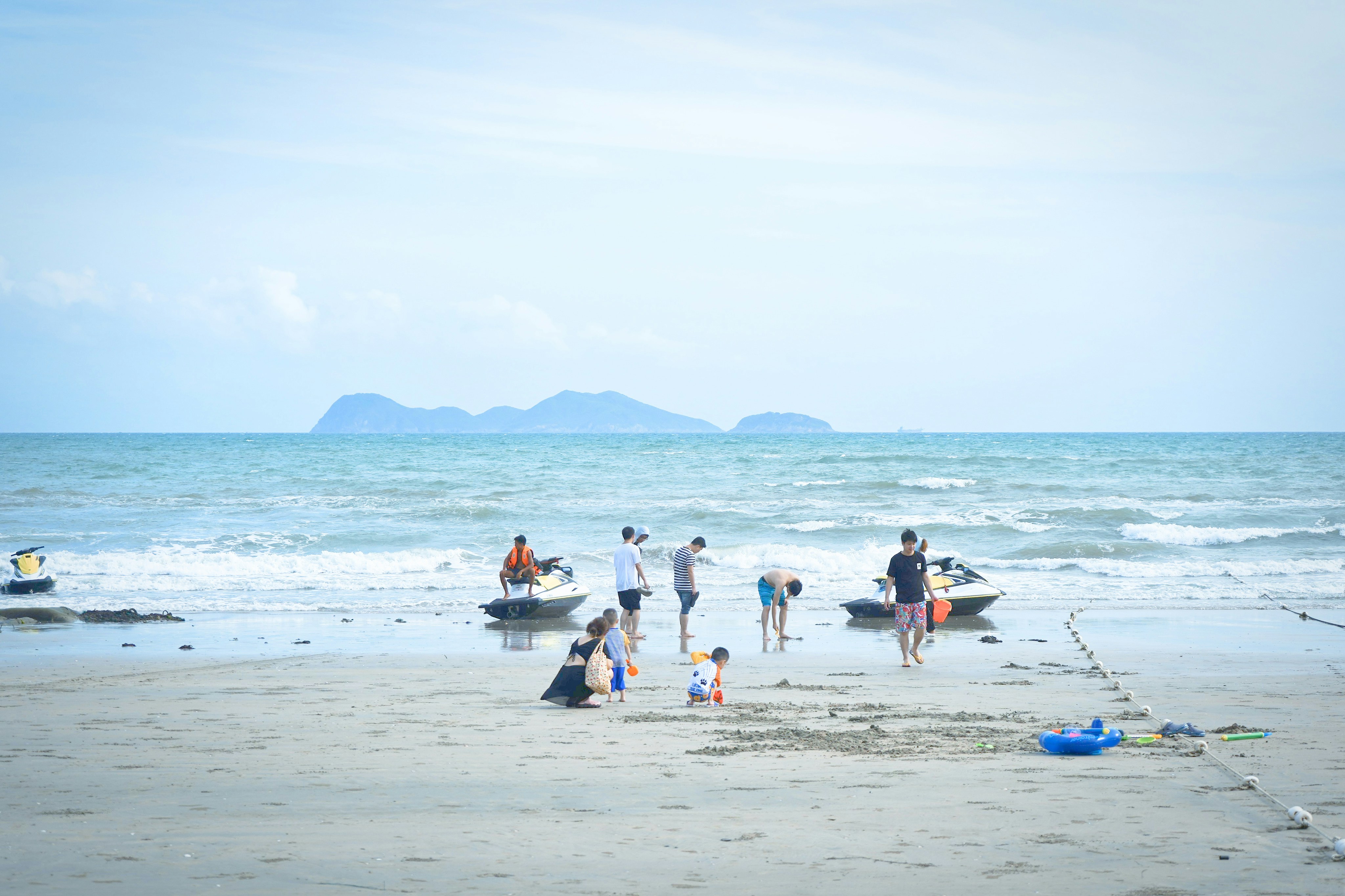 Shoreline Interlude: Families at Play as Jet Skis Idle and Distant Islands Loom
