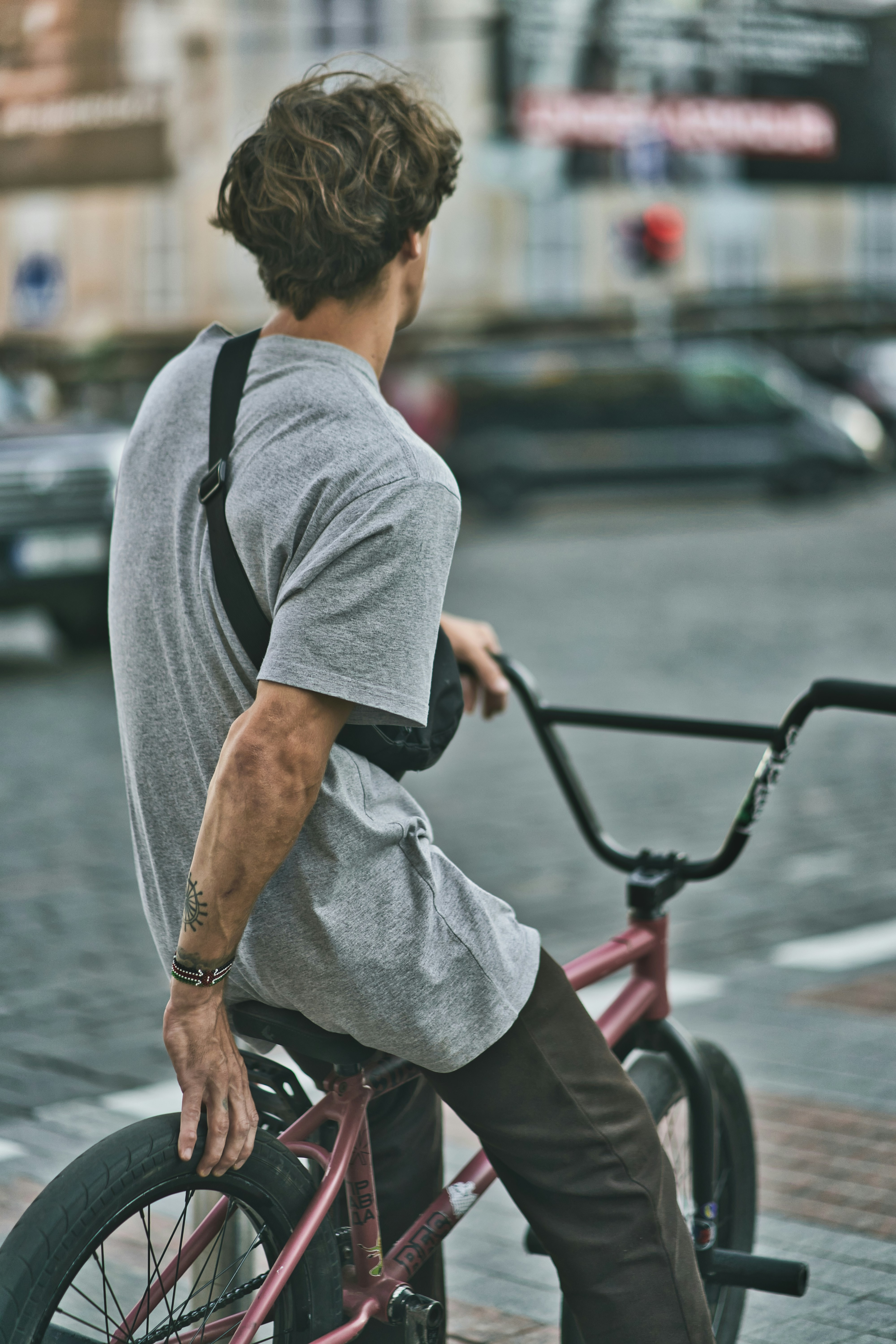 Back-View Pause on a Pink Bicycle Amid a Soft-Focus City