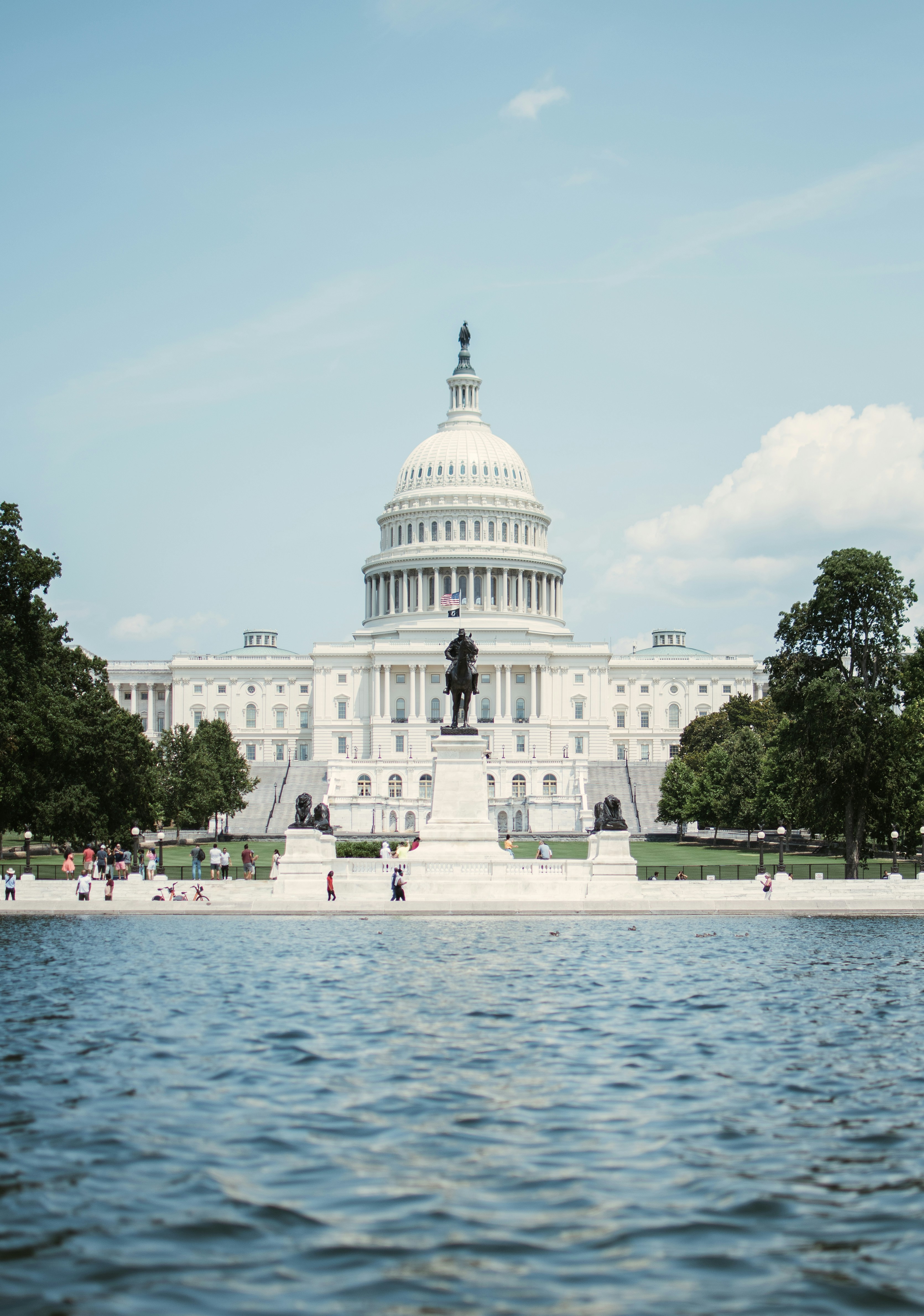 U.S. Capitol building framed by lush greenery and a reflective pool, showcasing the grandeur of American democracy.