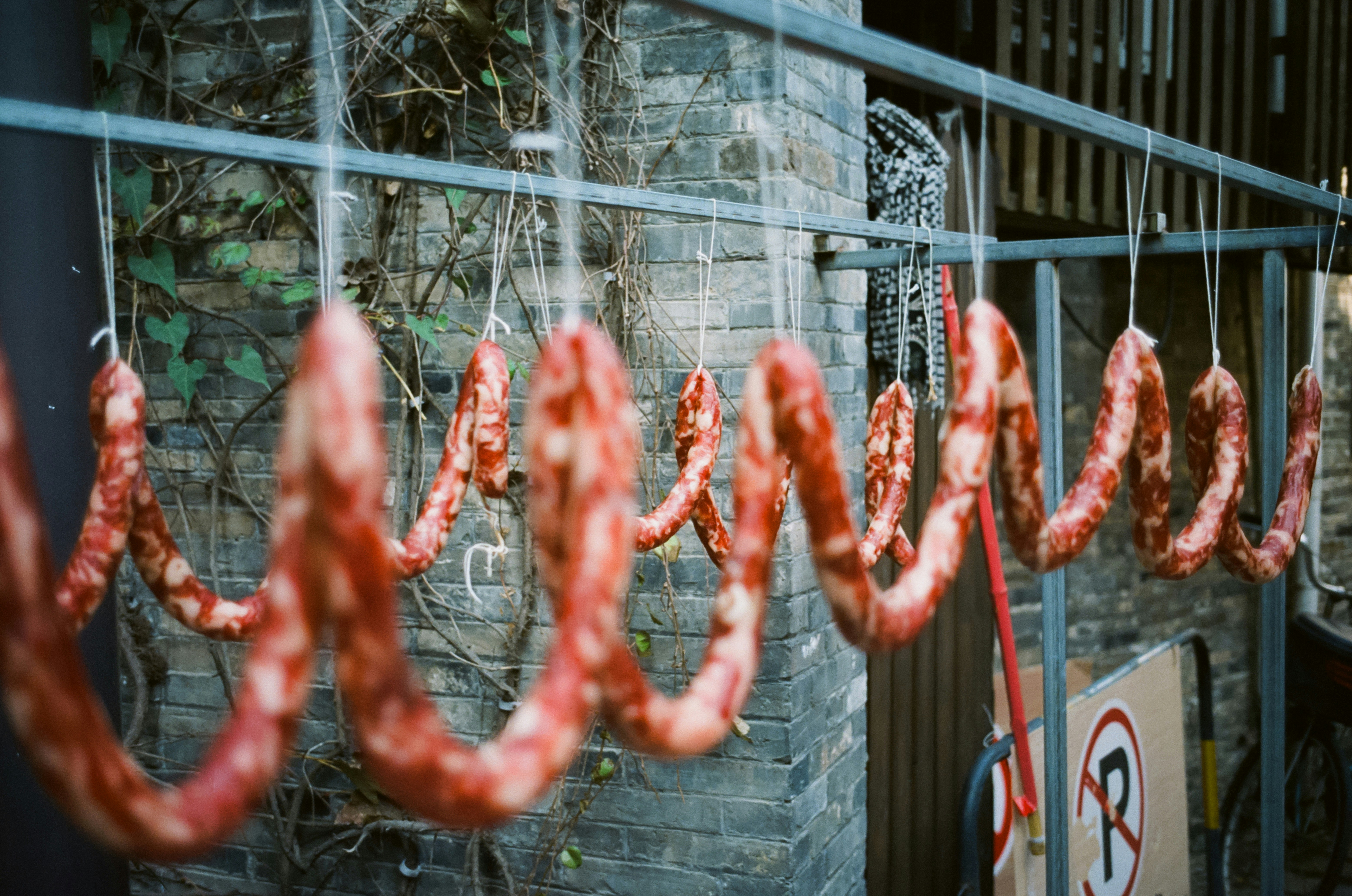 Hanging sausages create a rhythmic pattern against a rustic backdrop, showcasing traditional food preservation methods.