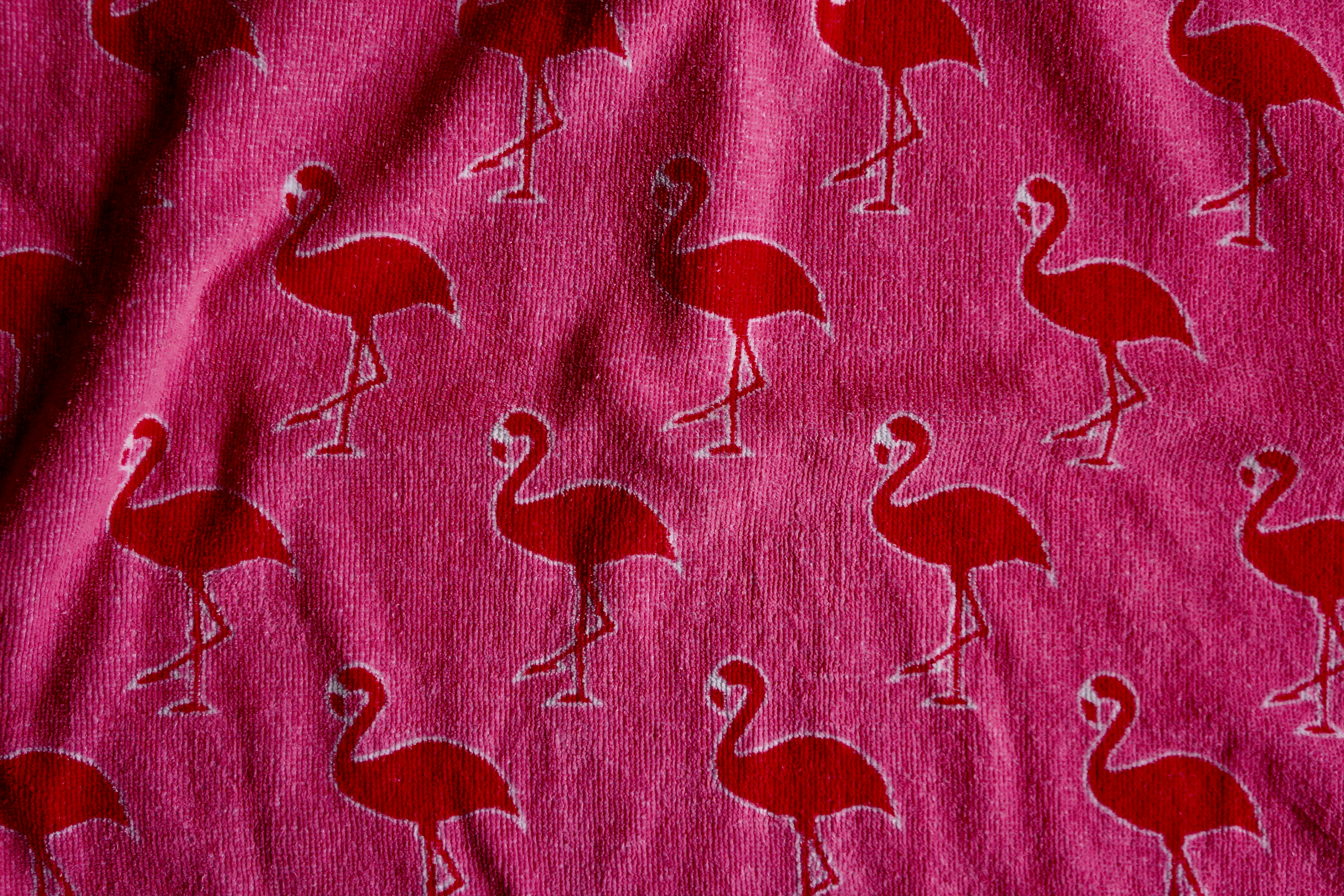 Patterned fabric featuring vibrant red flamingos against a pink background, showcasing a playful and tropical aesthetic.
