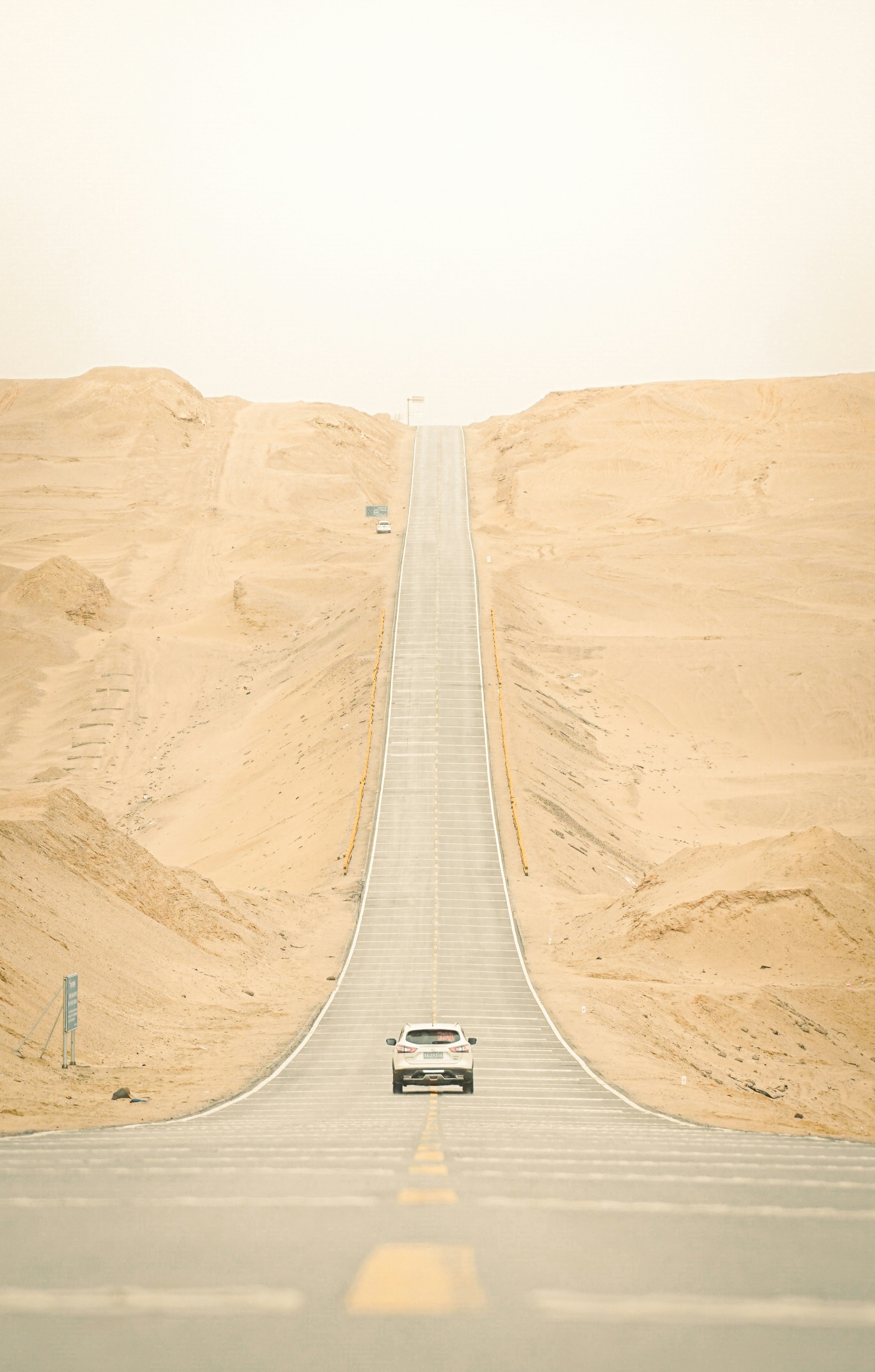 Pale Dunes, Stepped Highway: A Car's Ascend Toward the Quiet Horizon