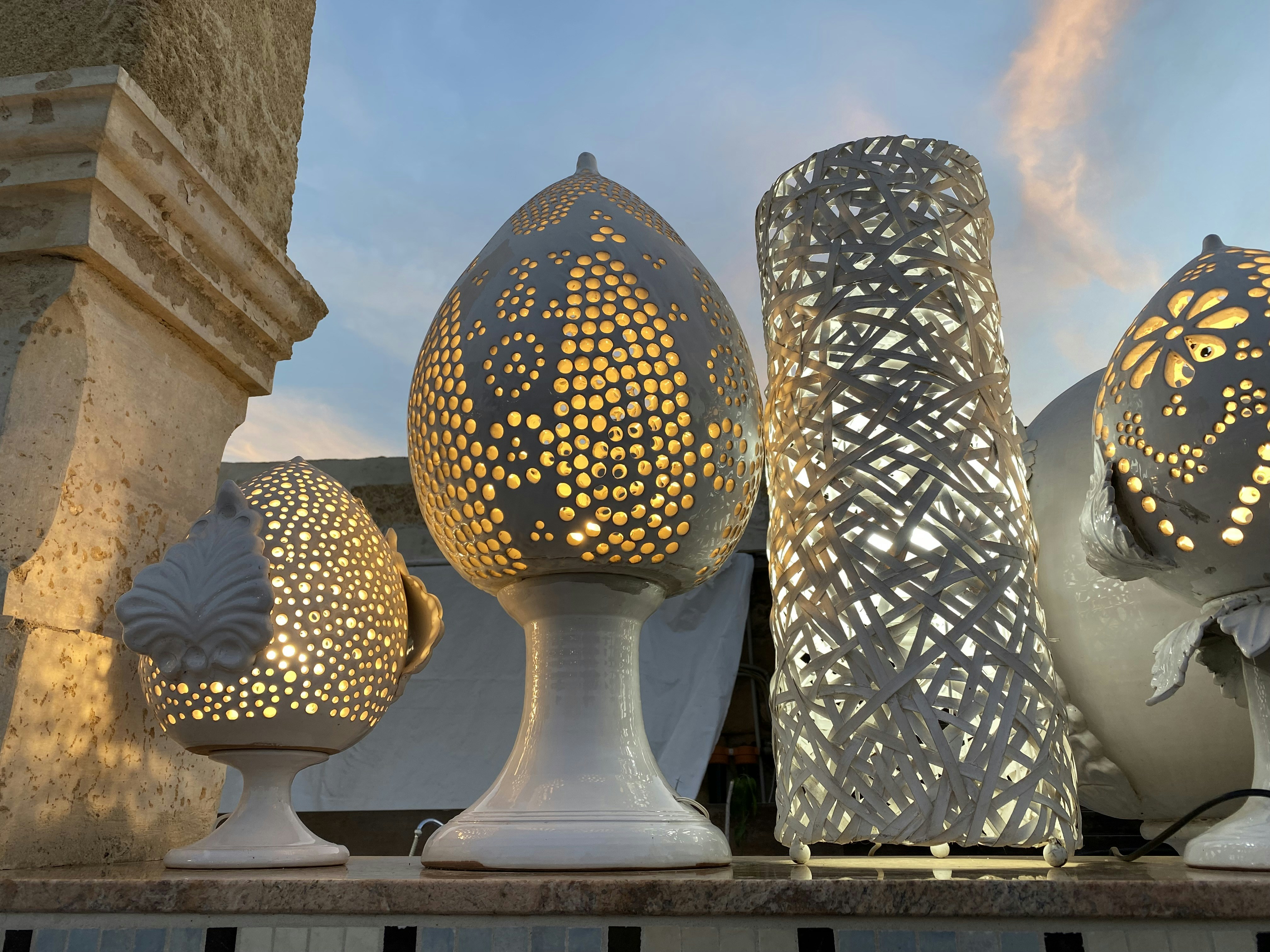 Ornate stone lamps from Salento glow warmly against a twilight sky.