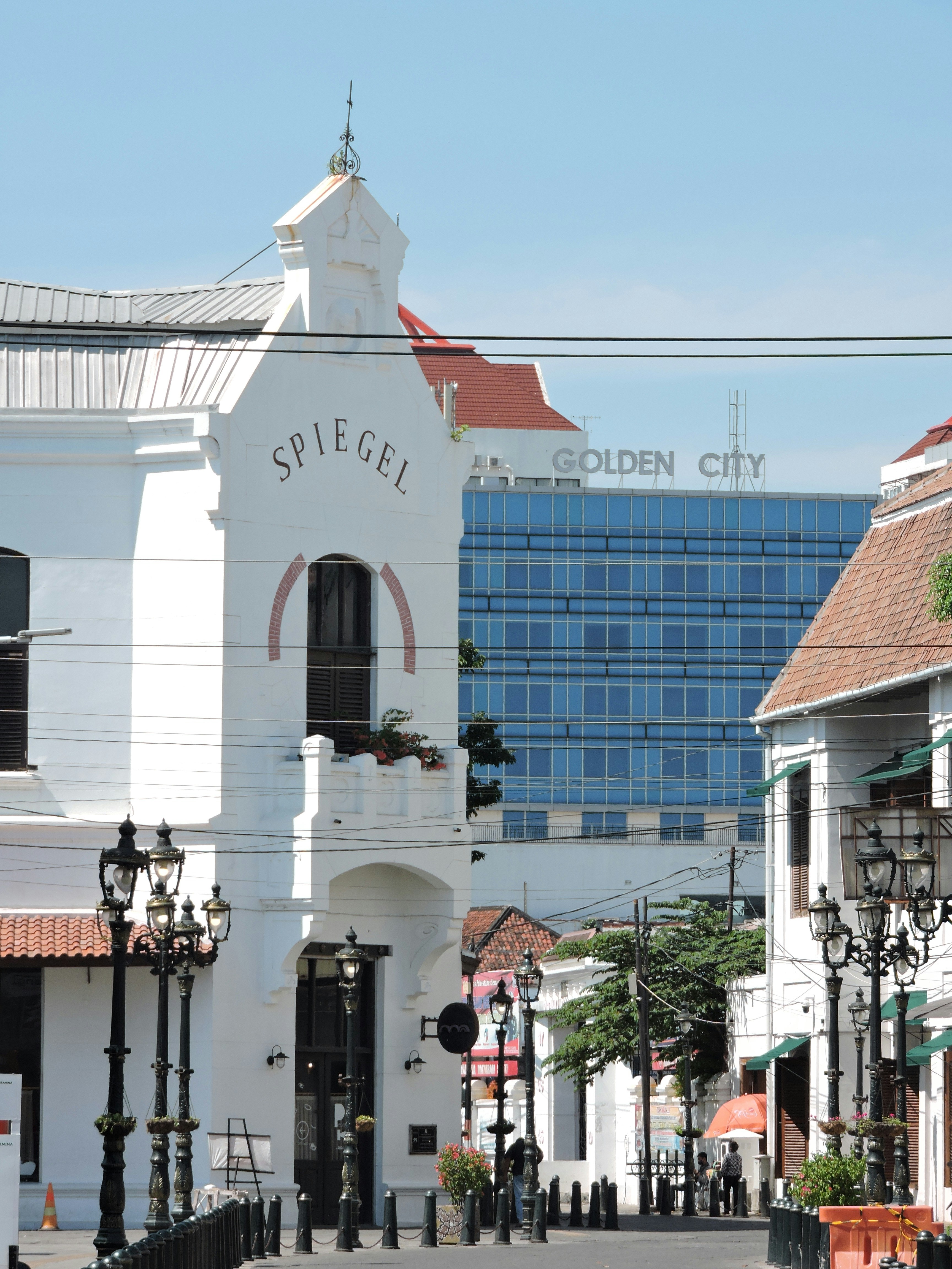 Historic building labeled 'Spiegel' stands prominently in a bustling urban setting, juxtaposed against a modern skyscraper in the background.