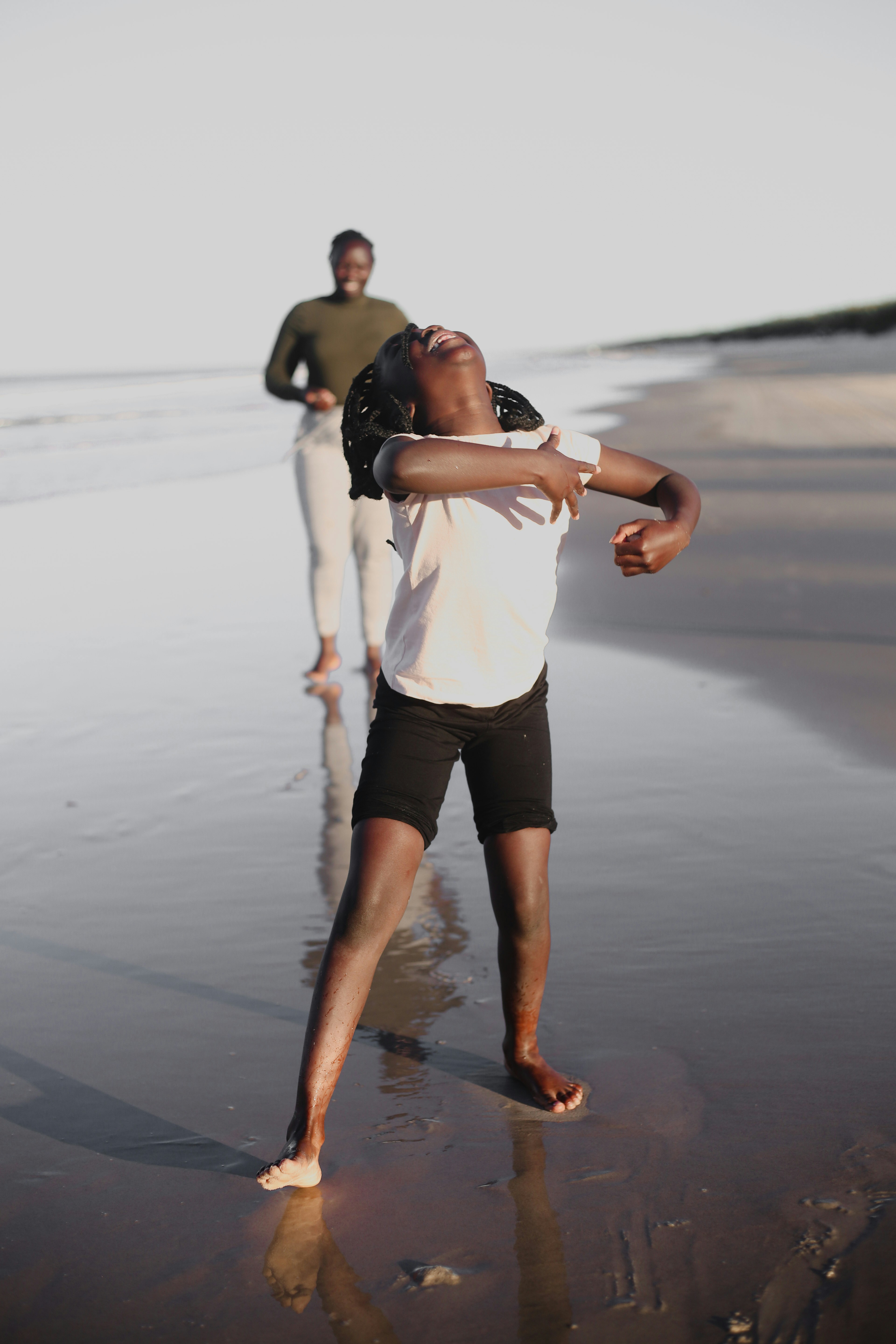 Sunlit Shoreline Dance: A Child's Freestyle Joy on Wet Sand