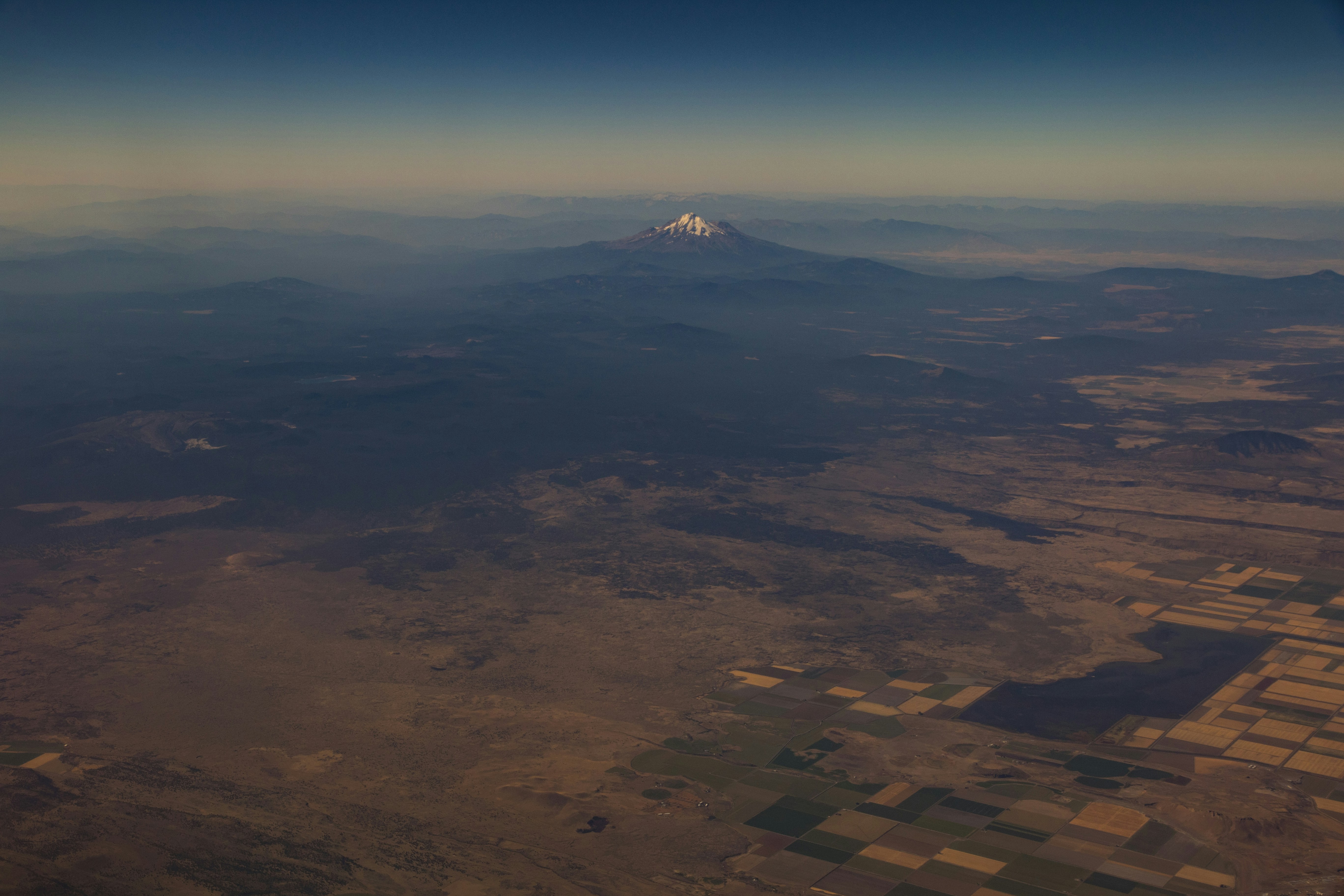 Horizon Sentinel: Snow-Capped Peak Above Patchwork Plains