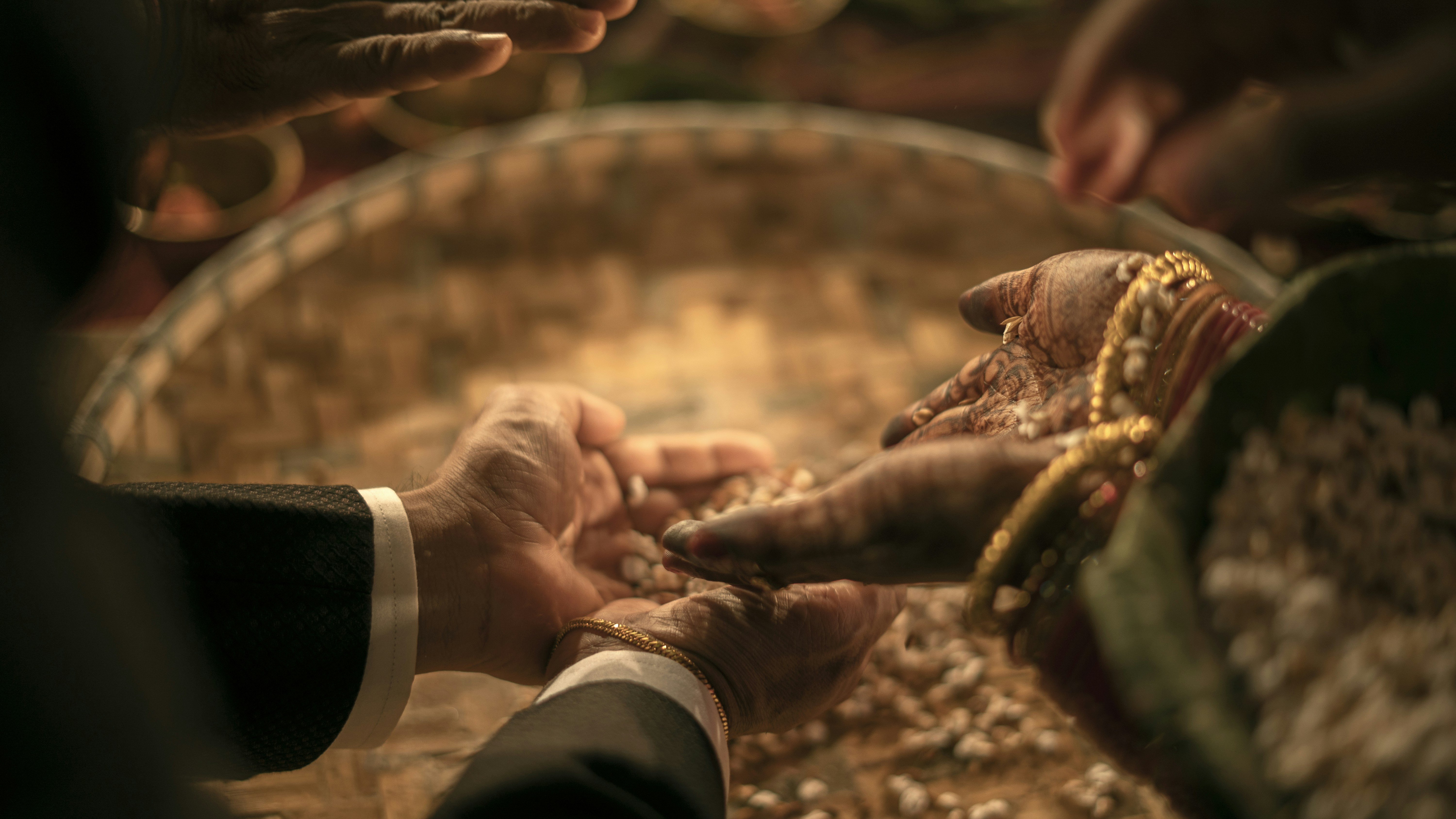 Hands exchanging grains during a cultural ritual, symbolizing unity and togetherness. The warm tones and intricate details highlight the significance of the moment.