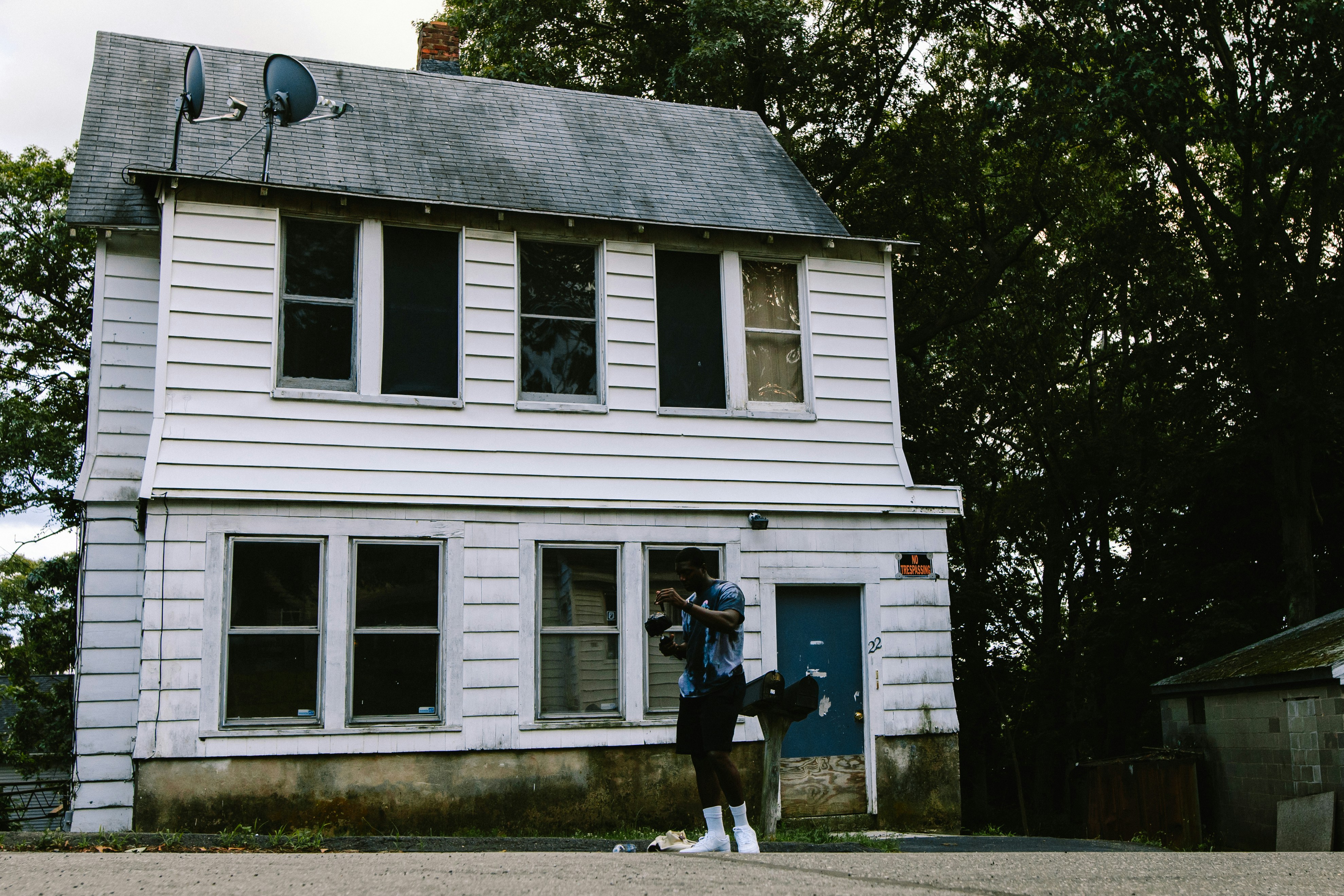 Rear-Window Target: A lone photographer outside a weathered two-story house