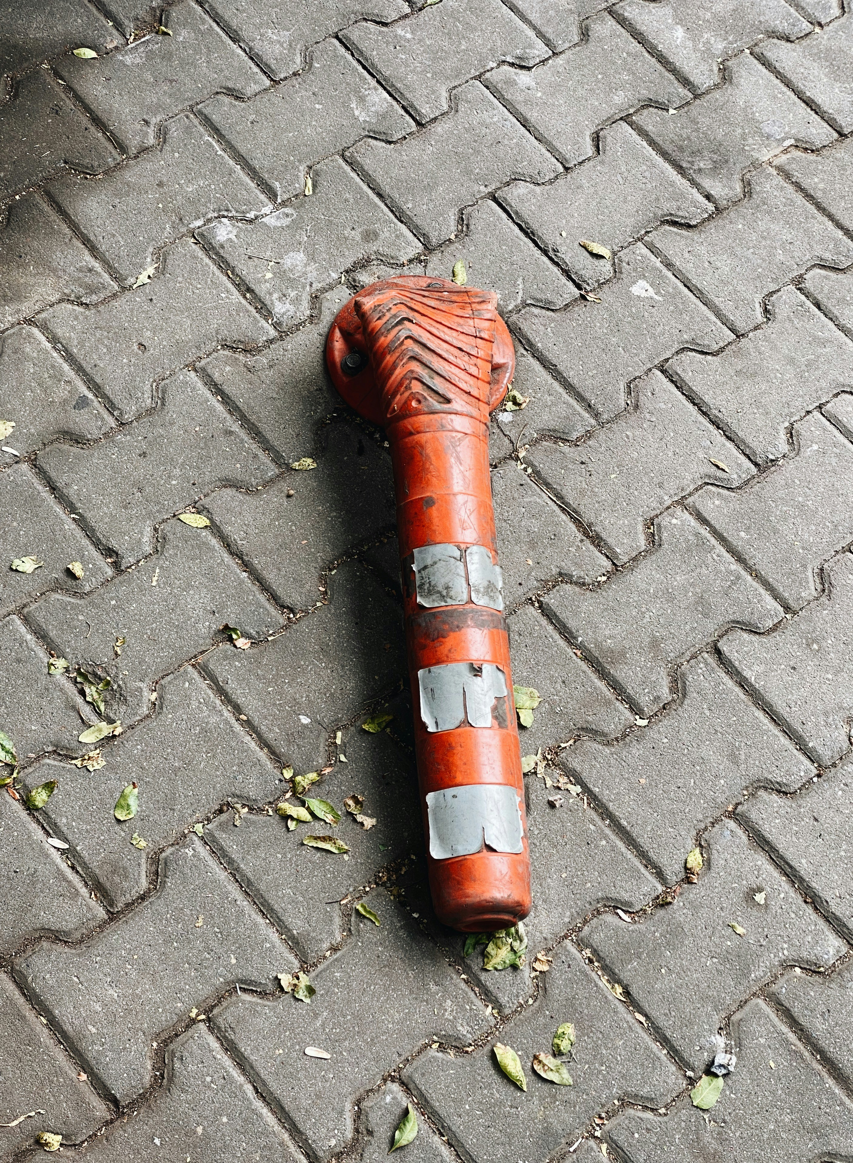 Orange safety baton resting on interlocking brick pavement