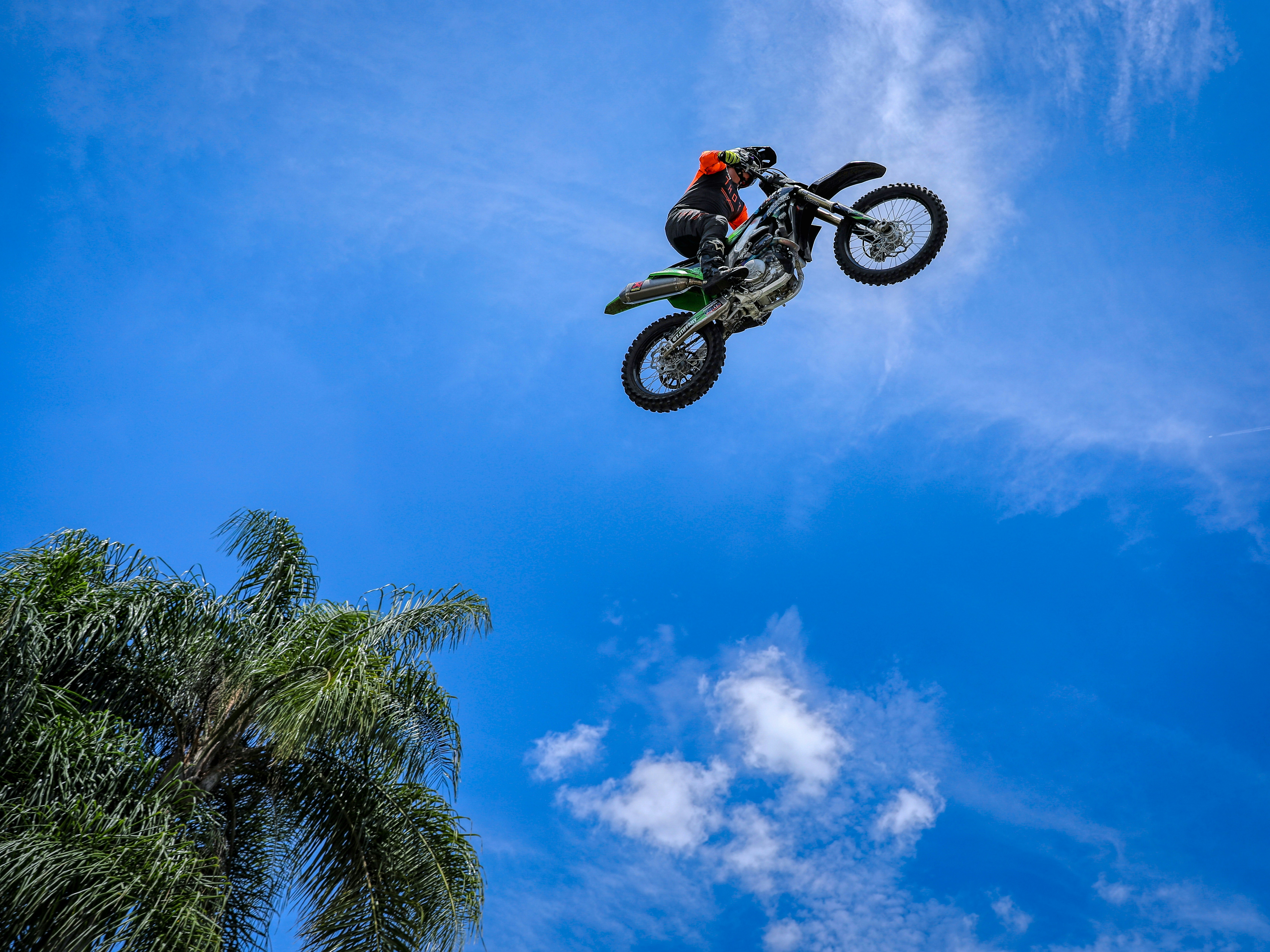 Airborne Gambit: motocross rider soars over a palm-fringed azure sky