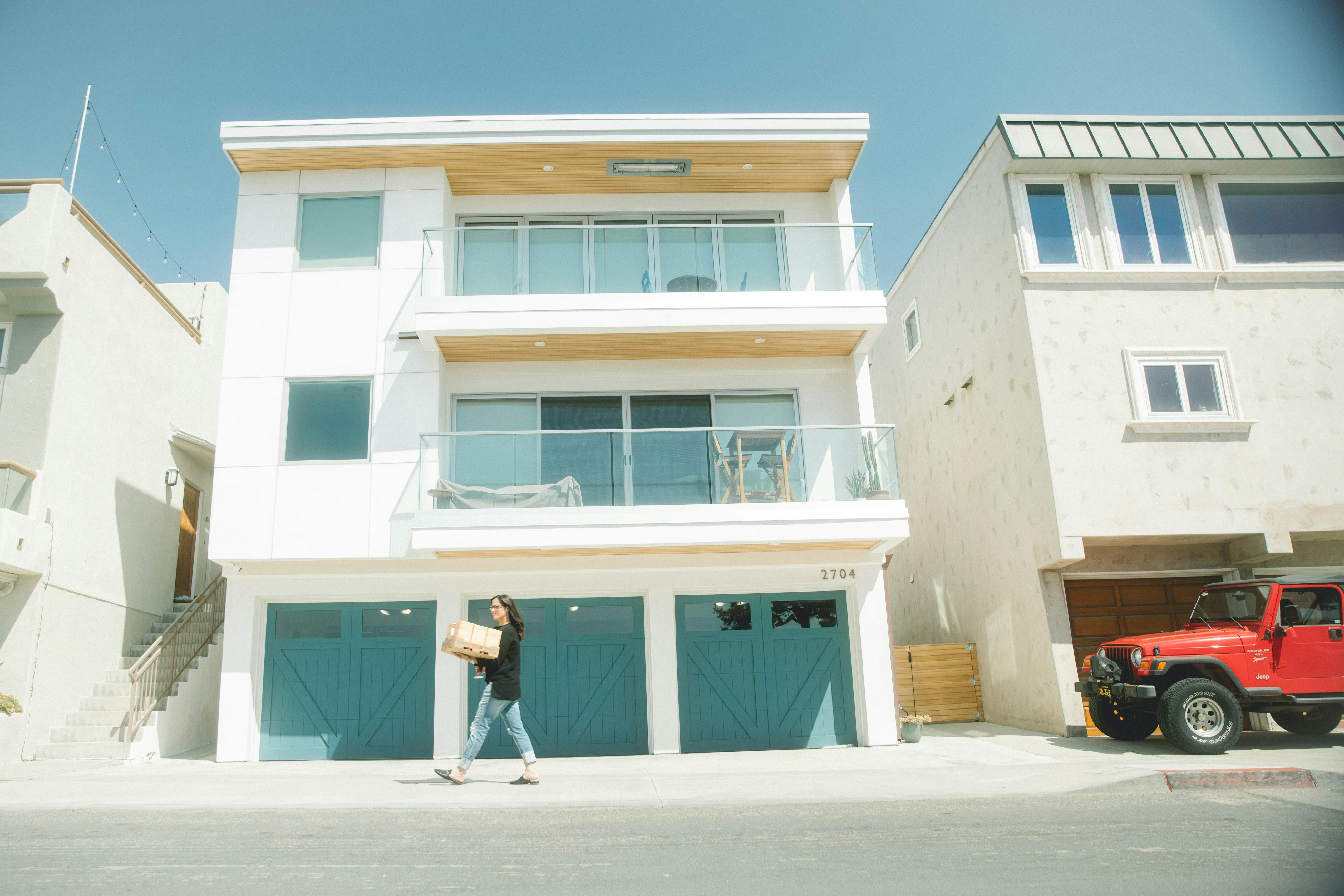 Sunlit Modern Townhouse with Glass Balconies and a Courier Carrying a Package