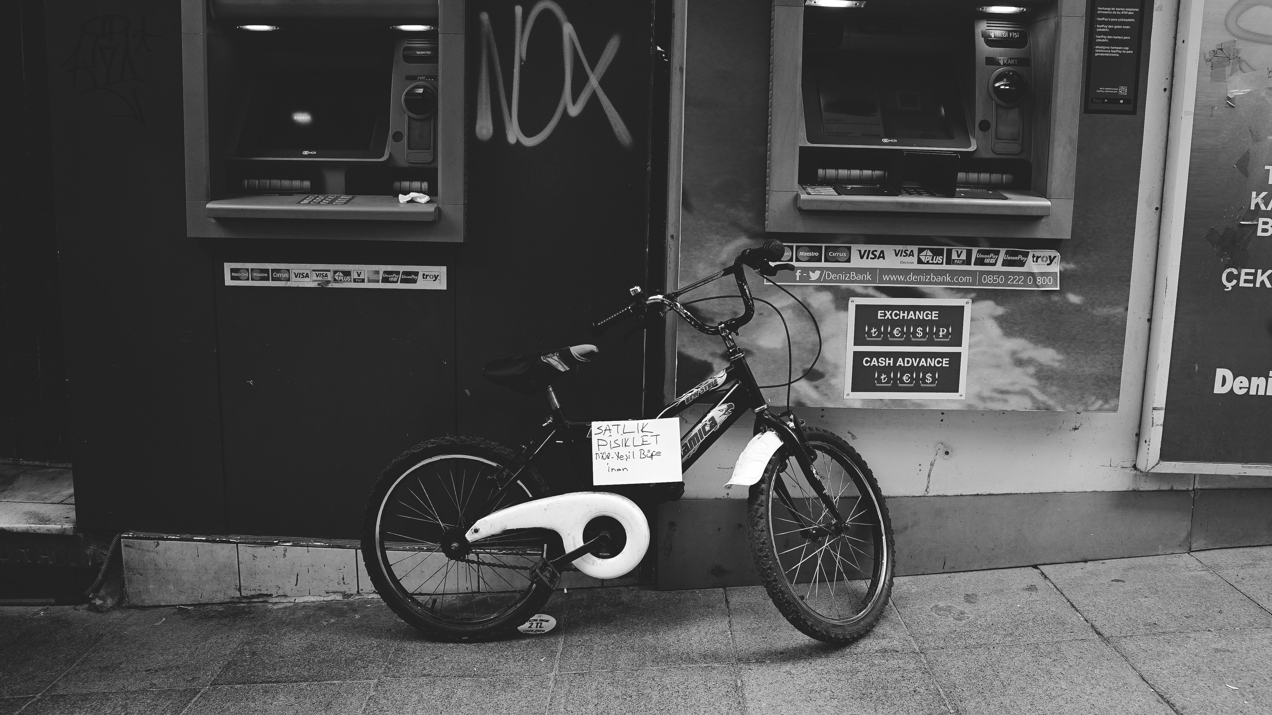grayscale photo of bicycle parked beside wall