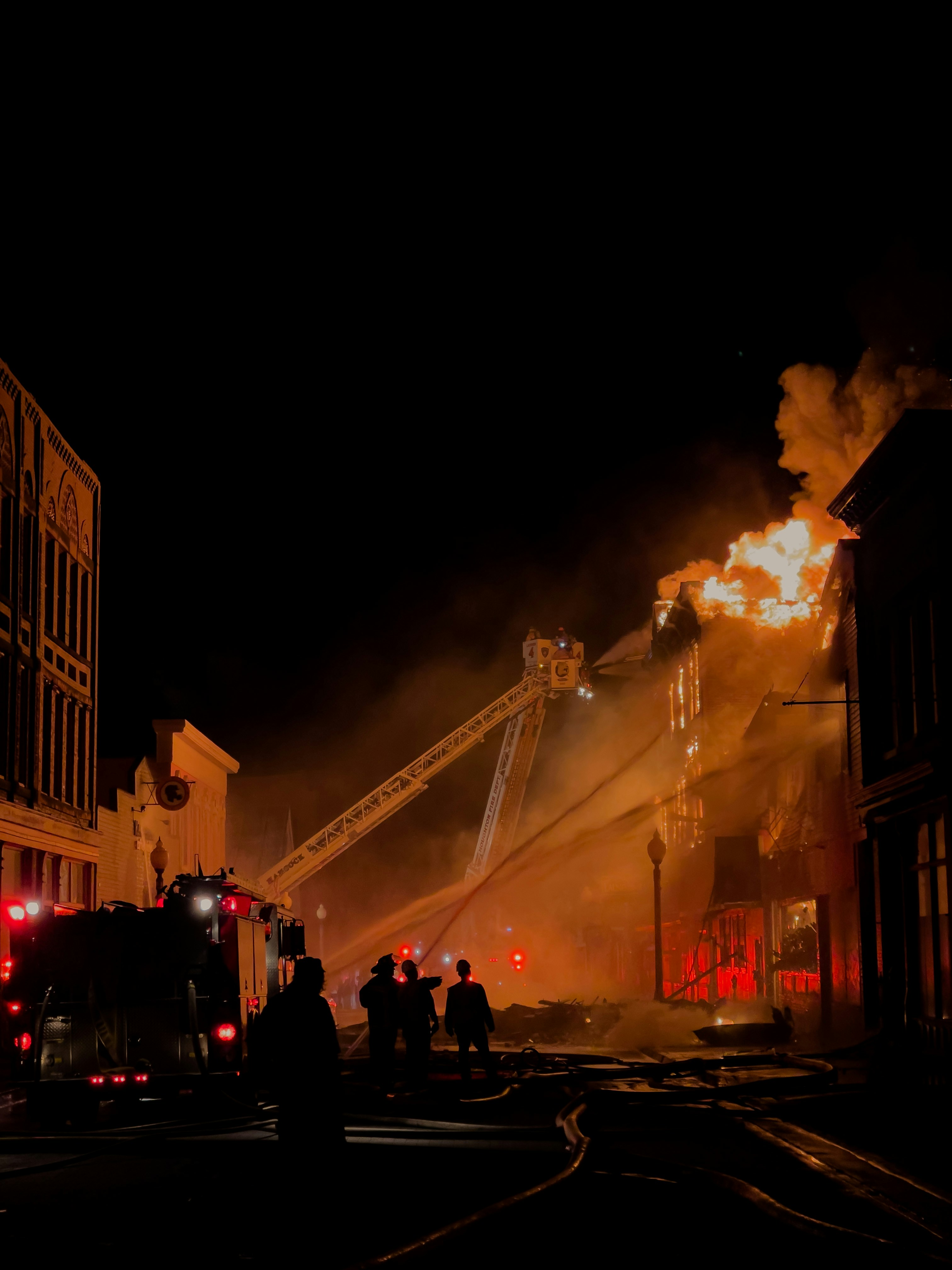 Firefighters combat a raging blaze engulfing a historic building at night, illuminated by flames and emergency lights.