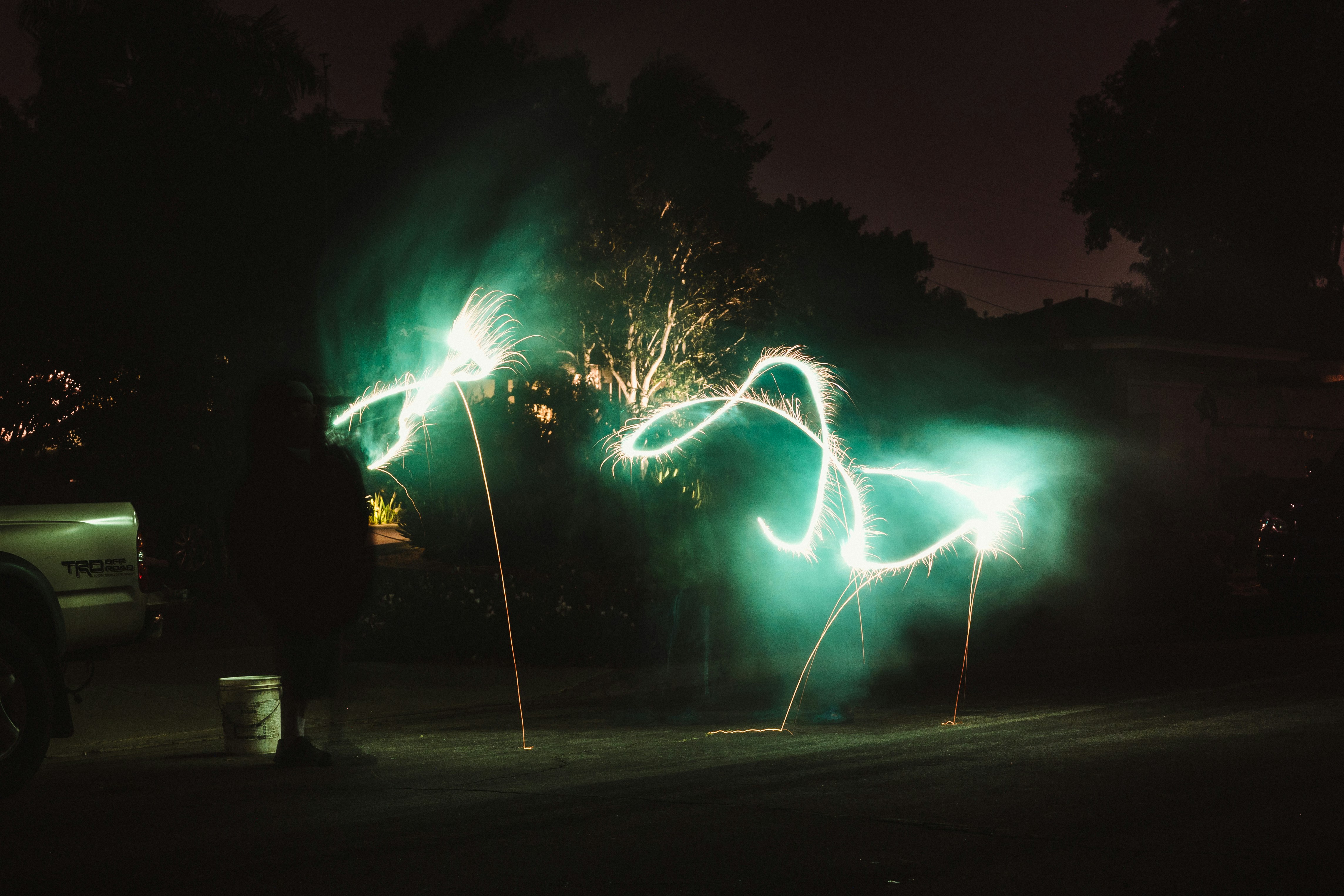 Man standing on road with fireworks display during night time photo ...