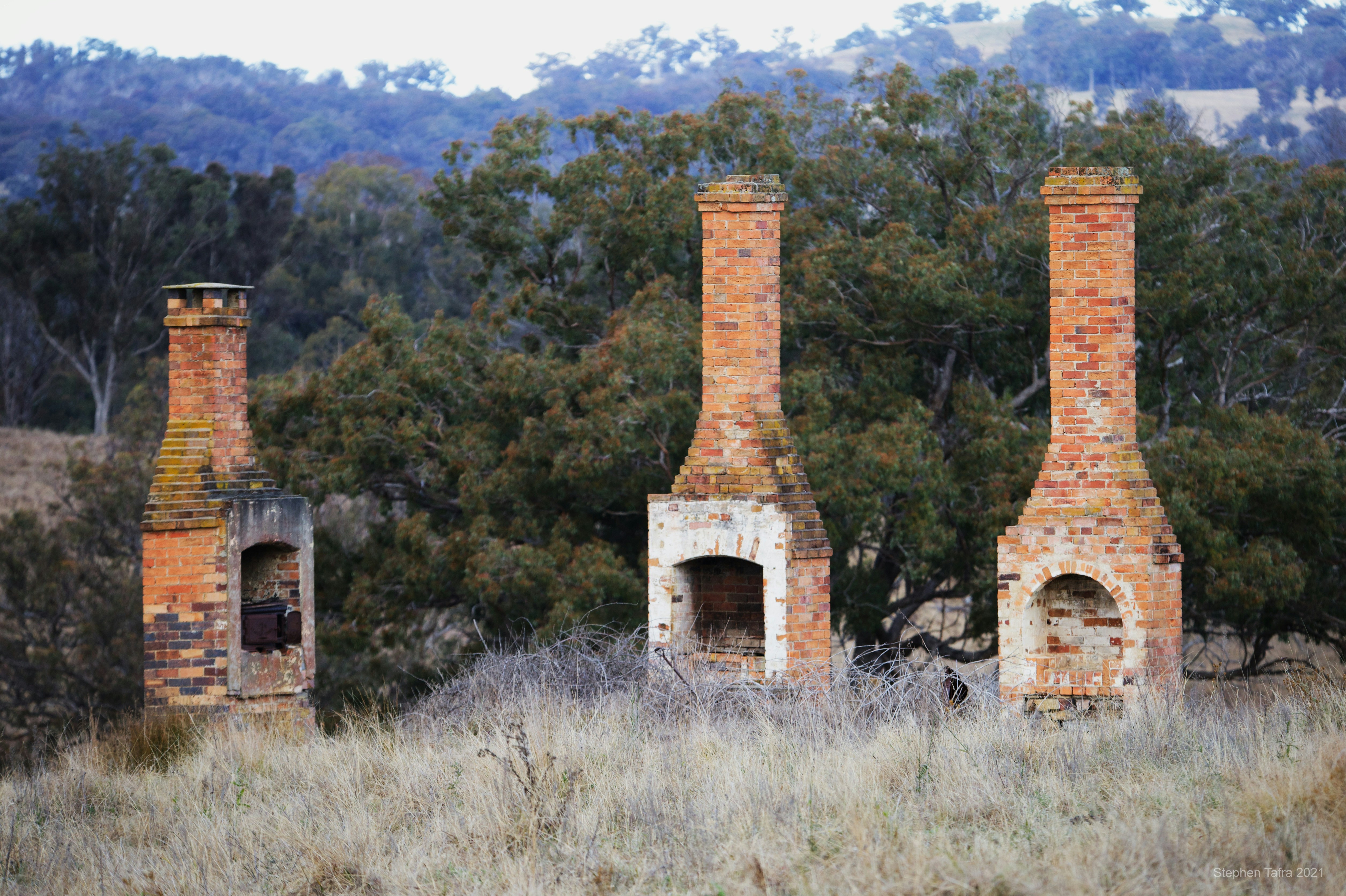 Triple Chimney Silhouettes in a Dry Grass Field