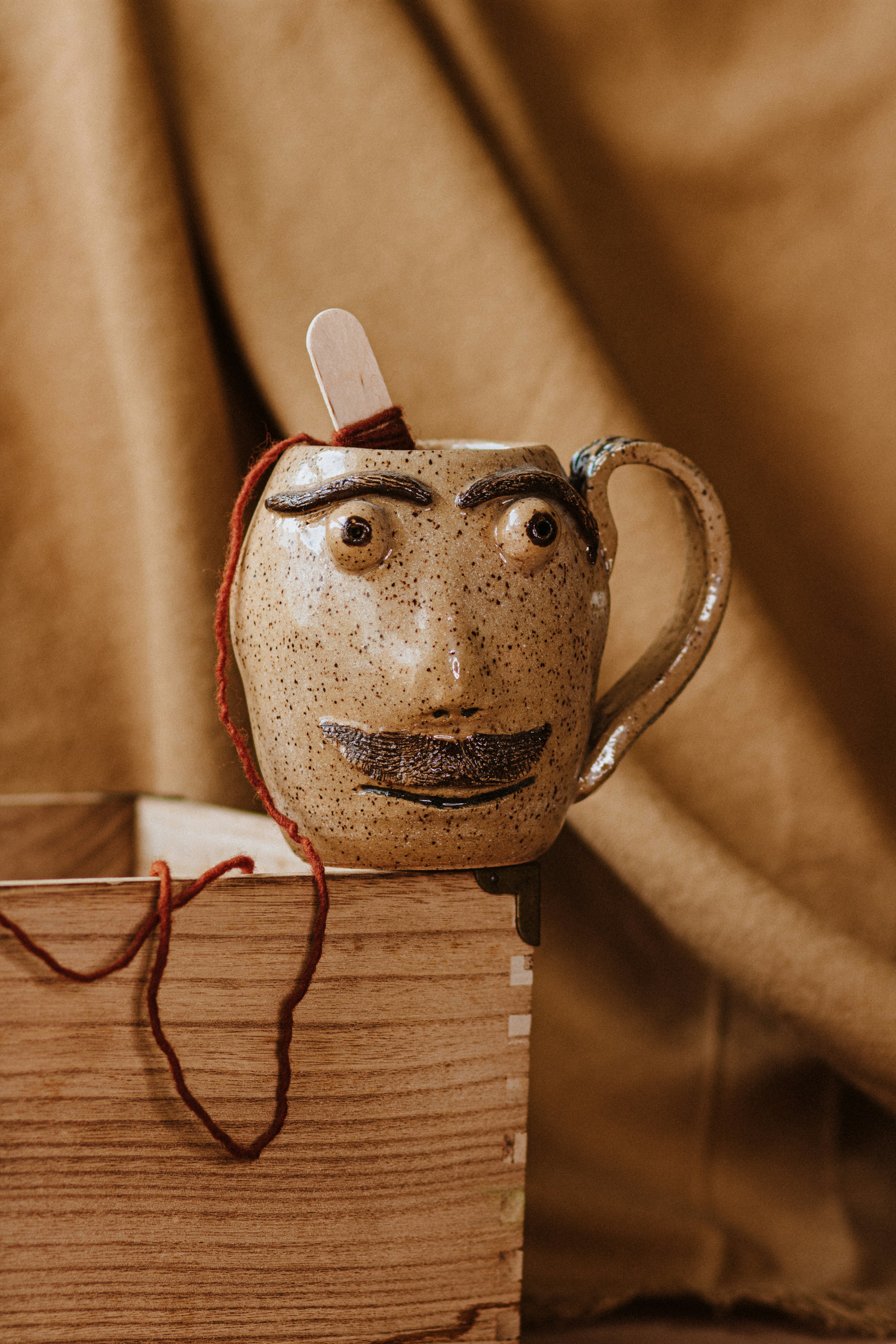 Pottery with simple earth tone backdrops. Wood and Ceramics. Fun Face Mug