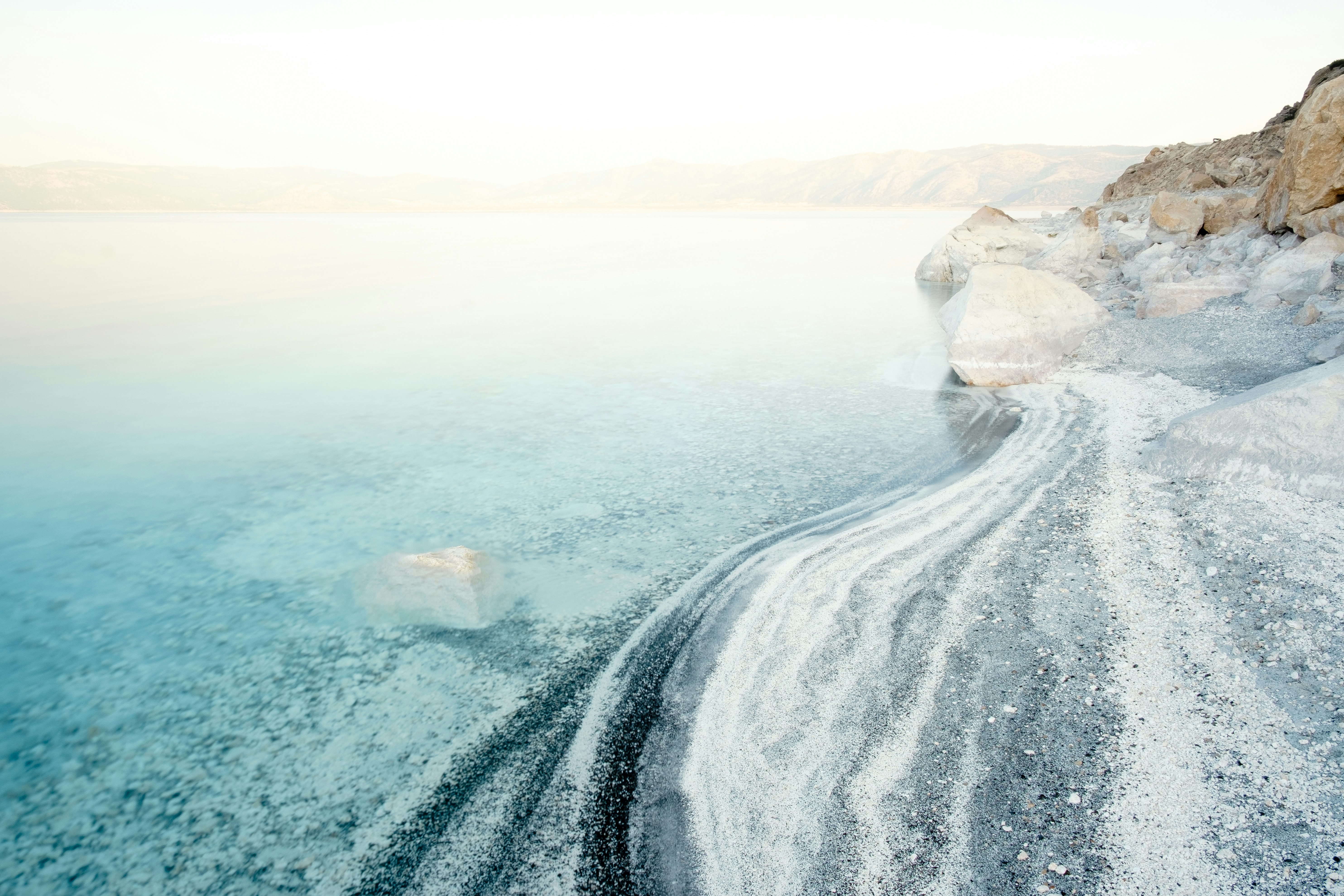 Turquoise waters meet black and white sands under a soft morning light at Lake Salda.